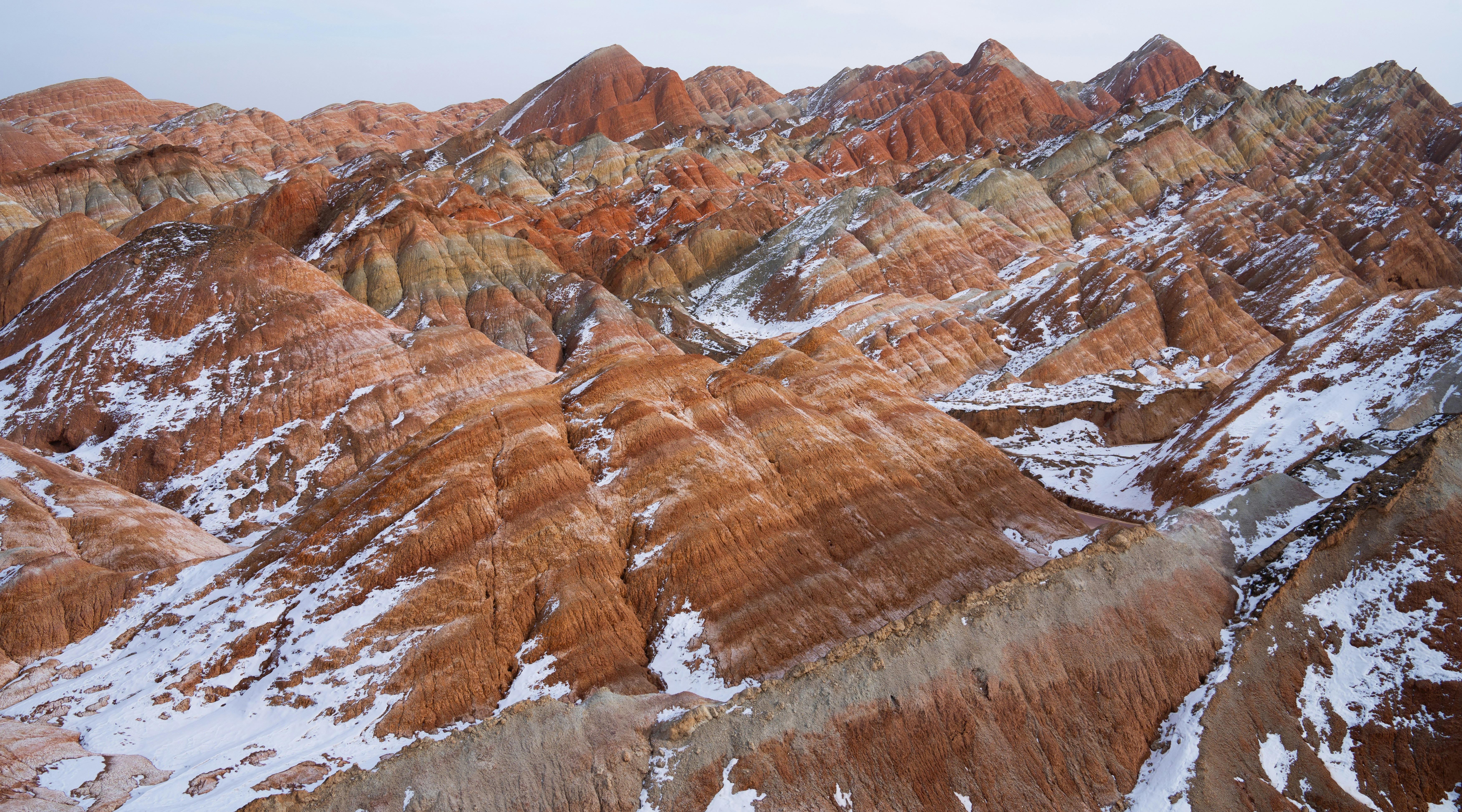 Crimson Ridges Under Snow: A Wave of Painted Valleys