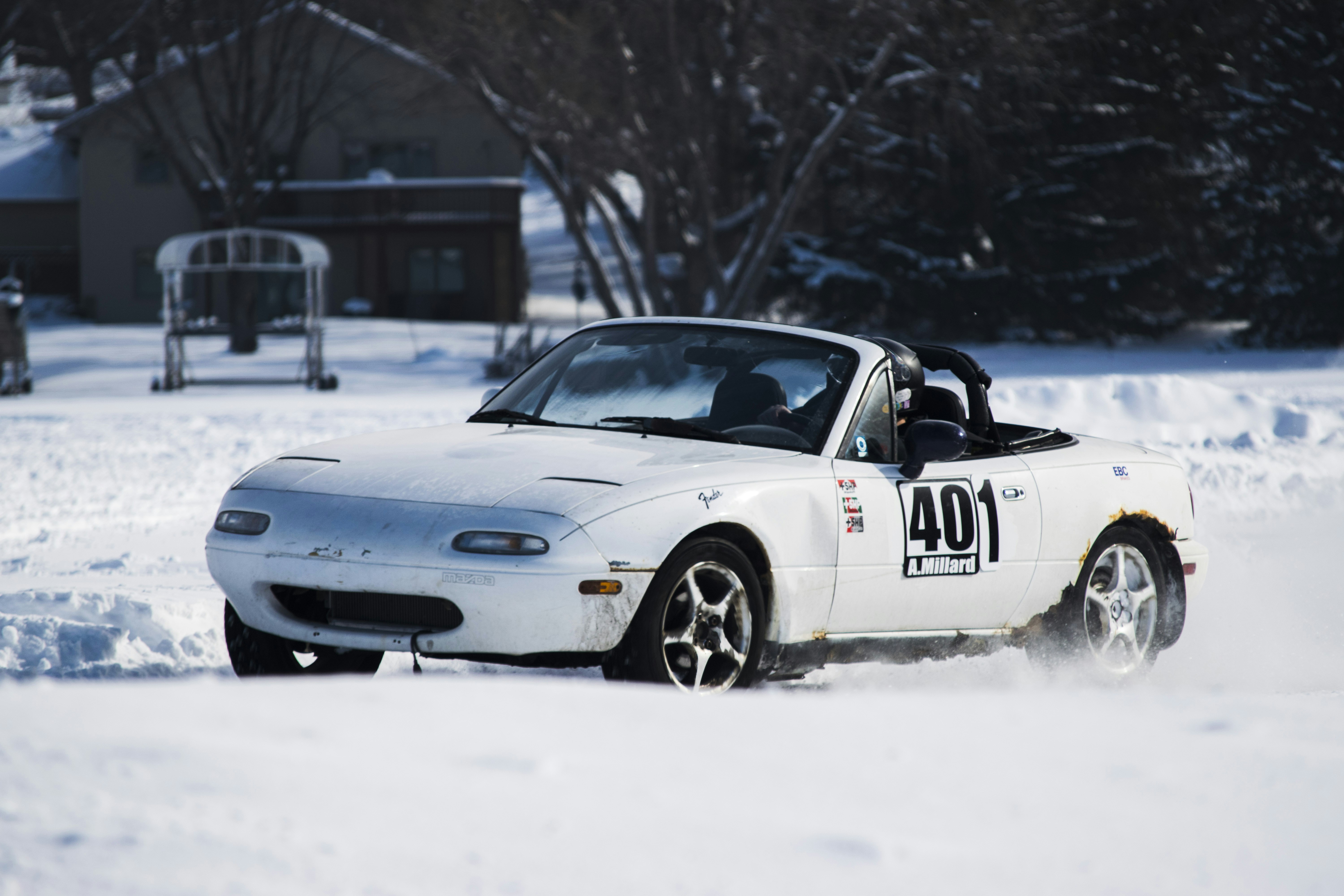 A white sports car driving down a snow covered road photo – Free Miata ...
