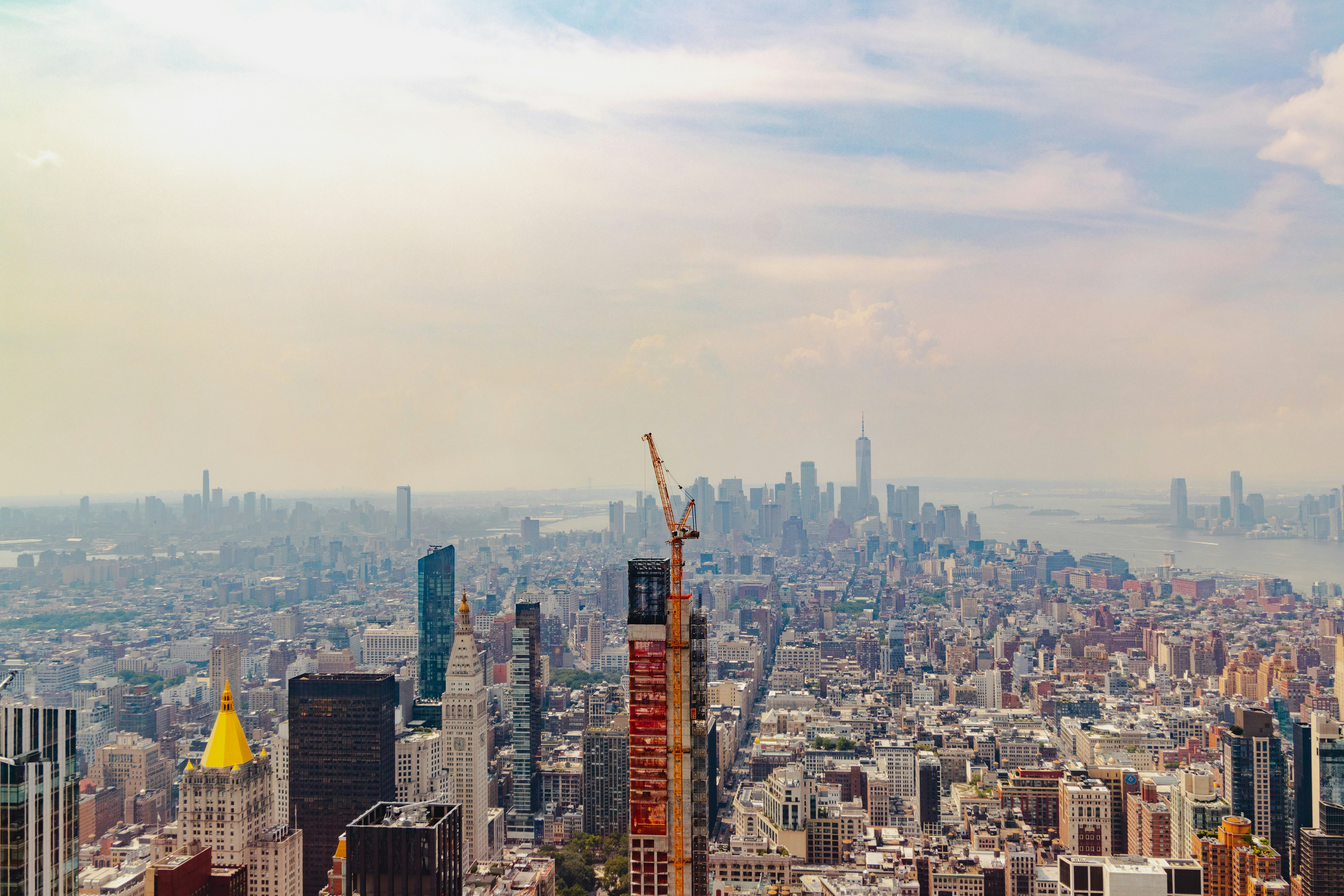 Cityscape with skyscrapers and a construction crane under a hazy sky.