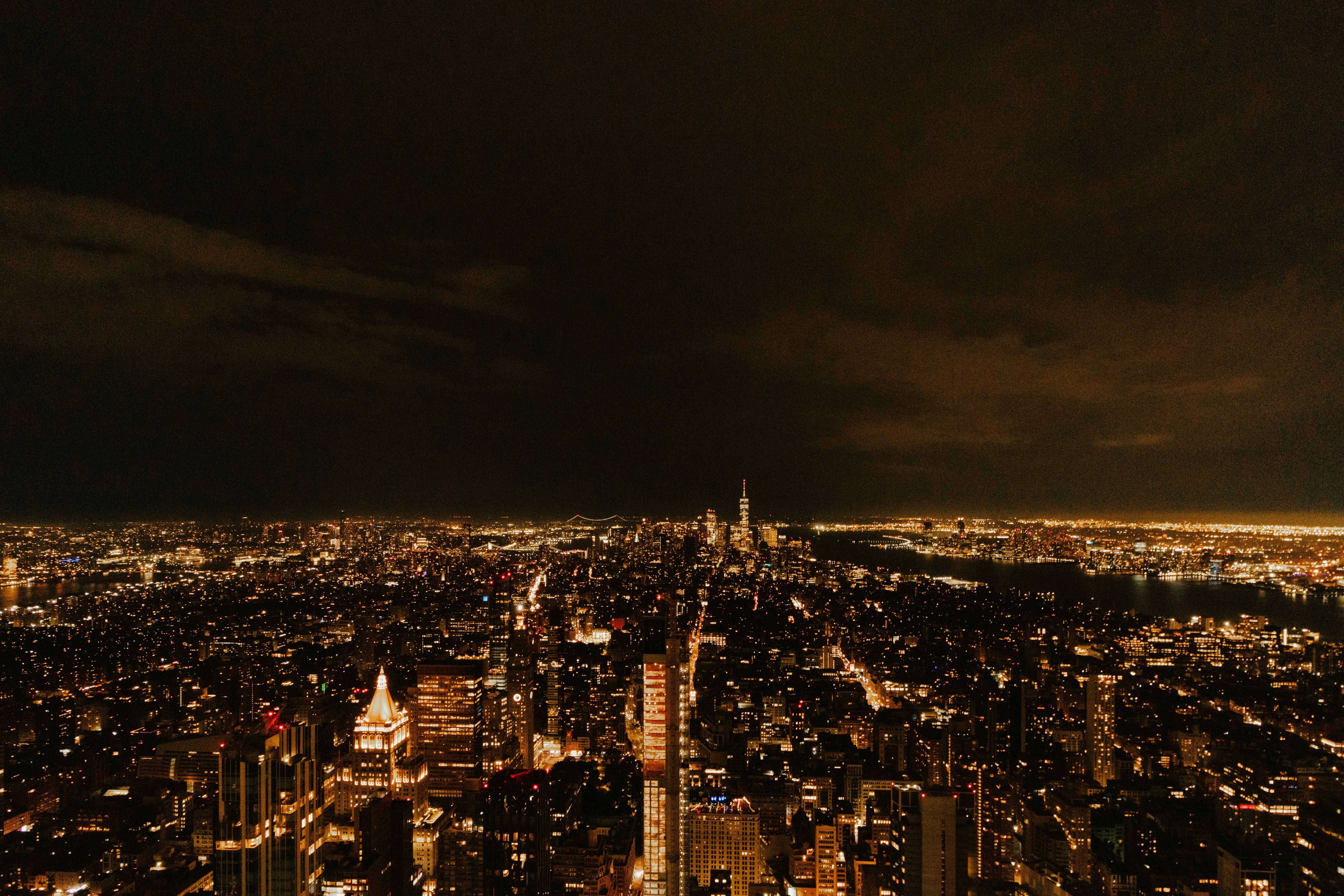 Vast cityscape with twinkling lights under a cloudy night sky.