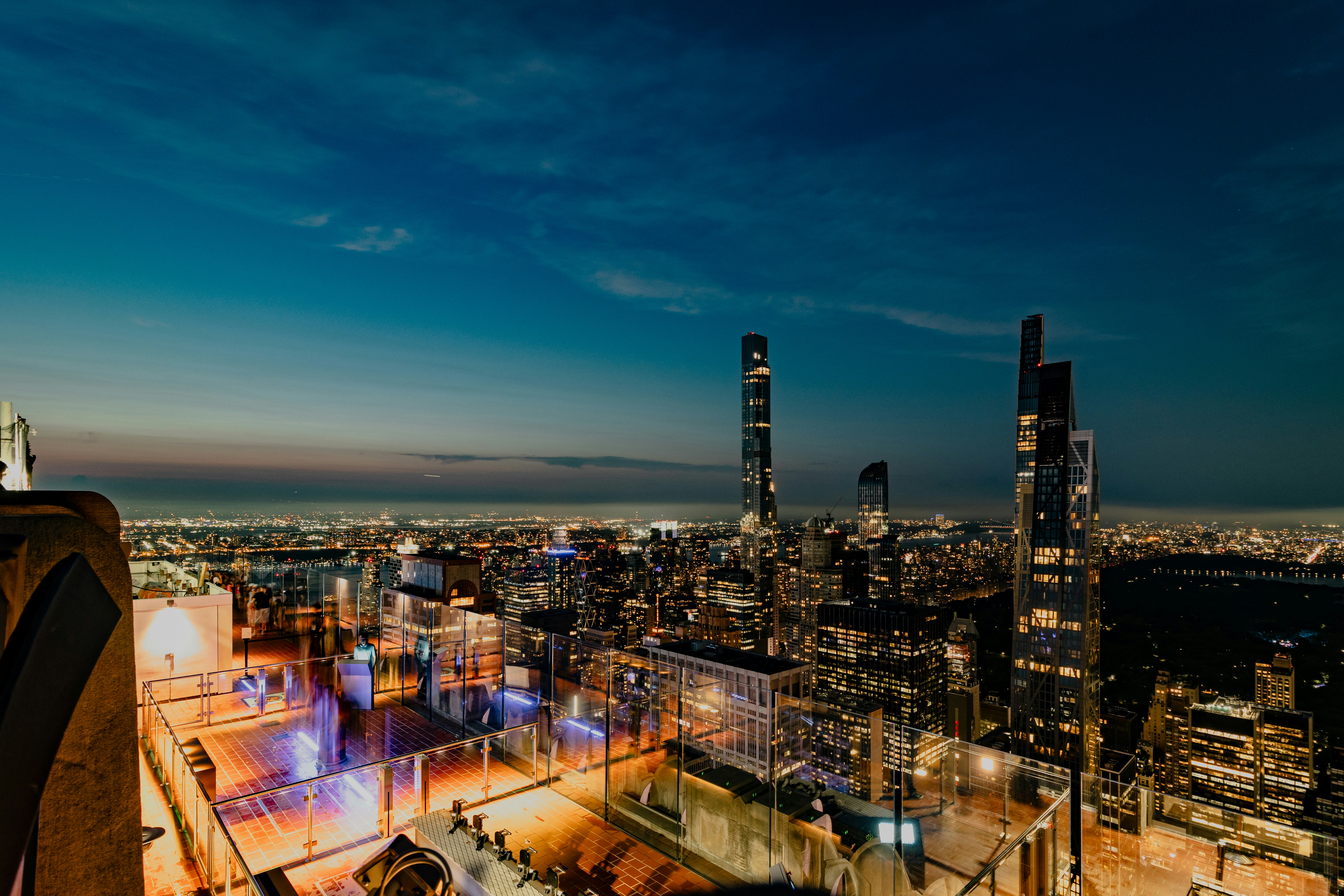 City skyline at twilight with skyscrapers silhouetted against a deepening blue sky and vibrant city lights below.