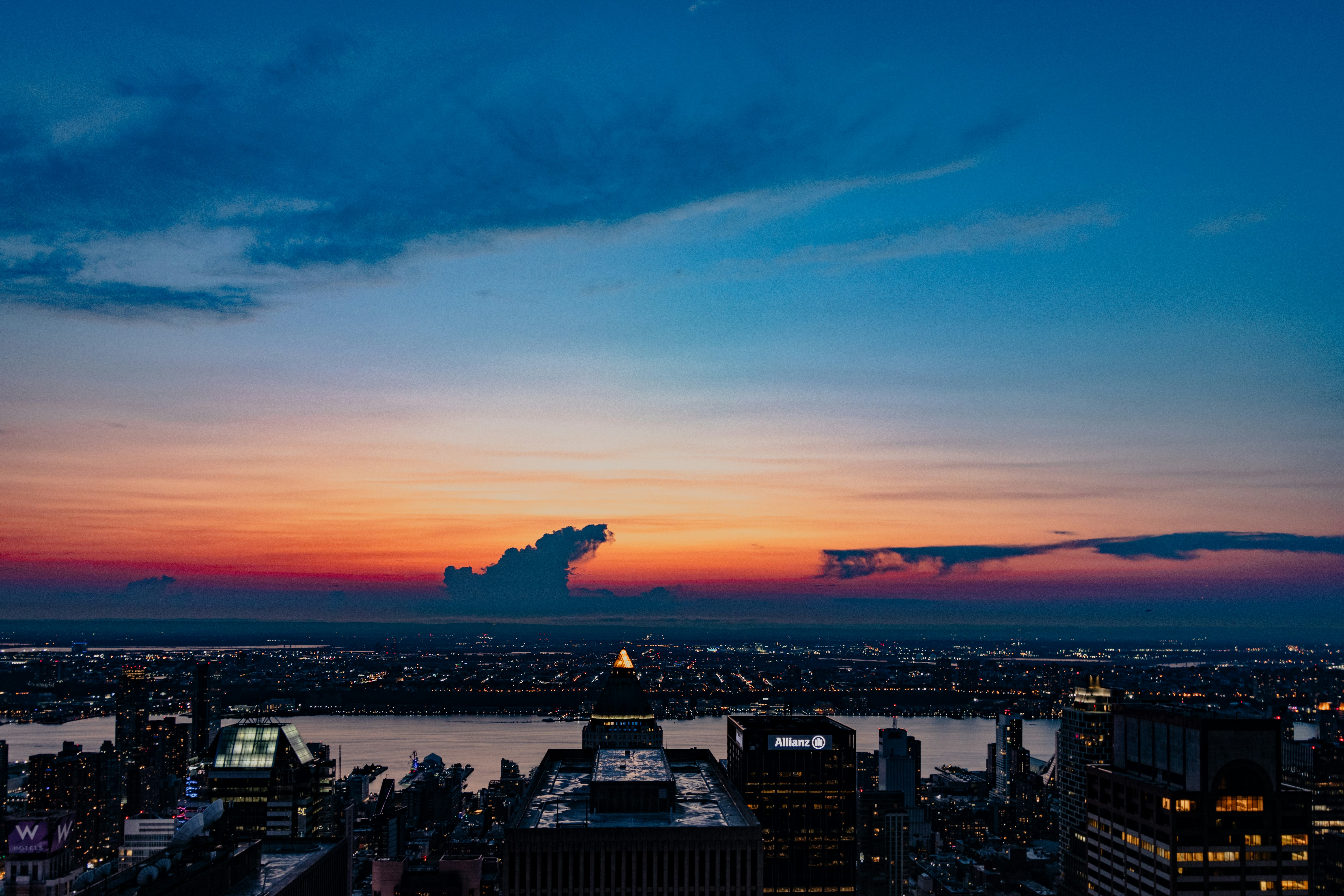 Colorful twilight sky over a city skyline with silhouetted buildings and twinkling lights.
