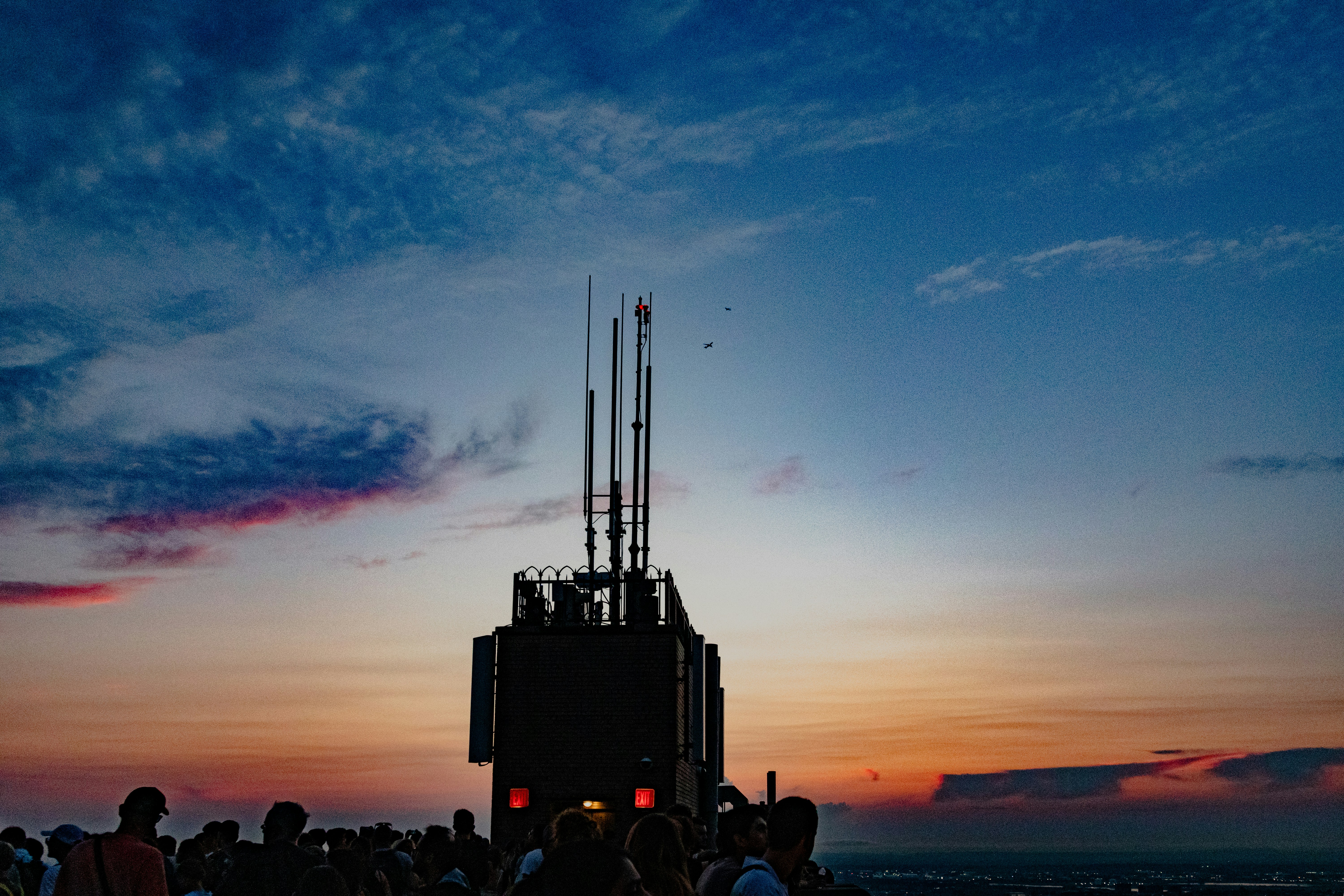 Silhouette of a tower and crowd against a vibrant sunset sky with transitioning colors from orange to blue.