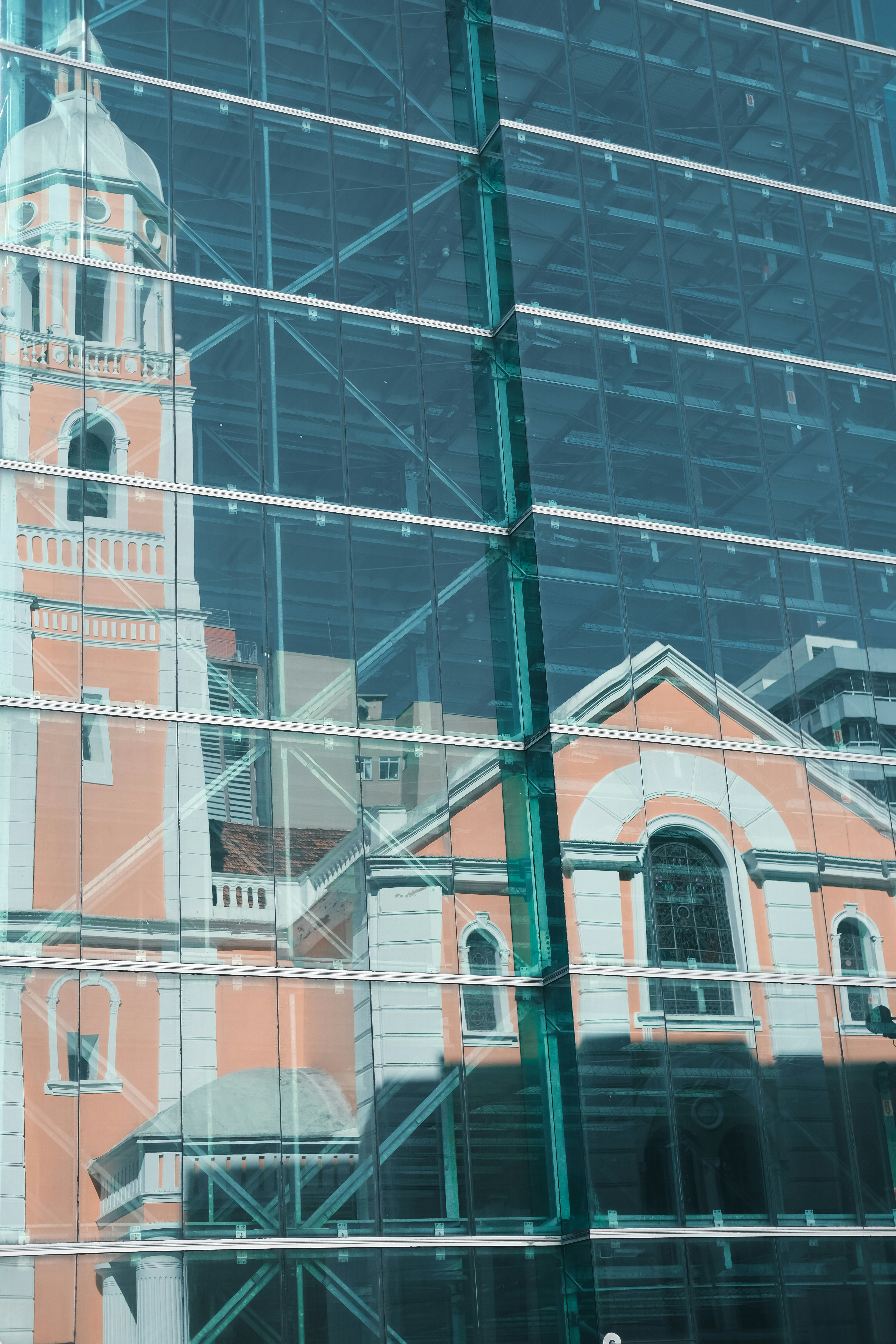 Historic church facade reflected in a modern glass building under a clear sky.