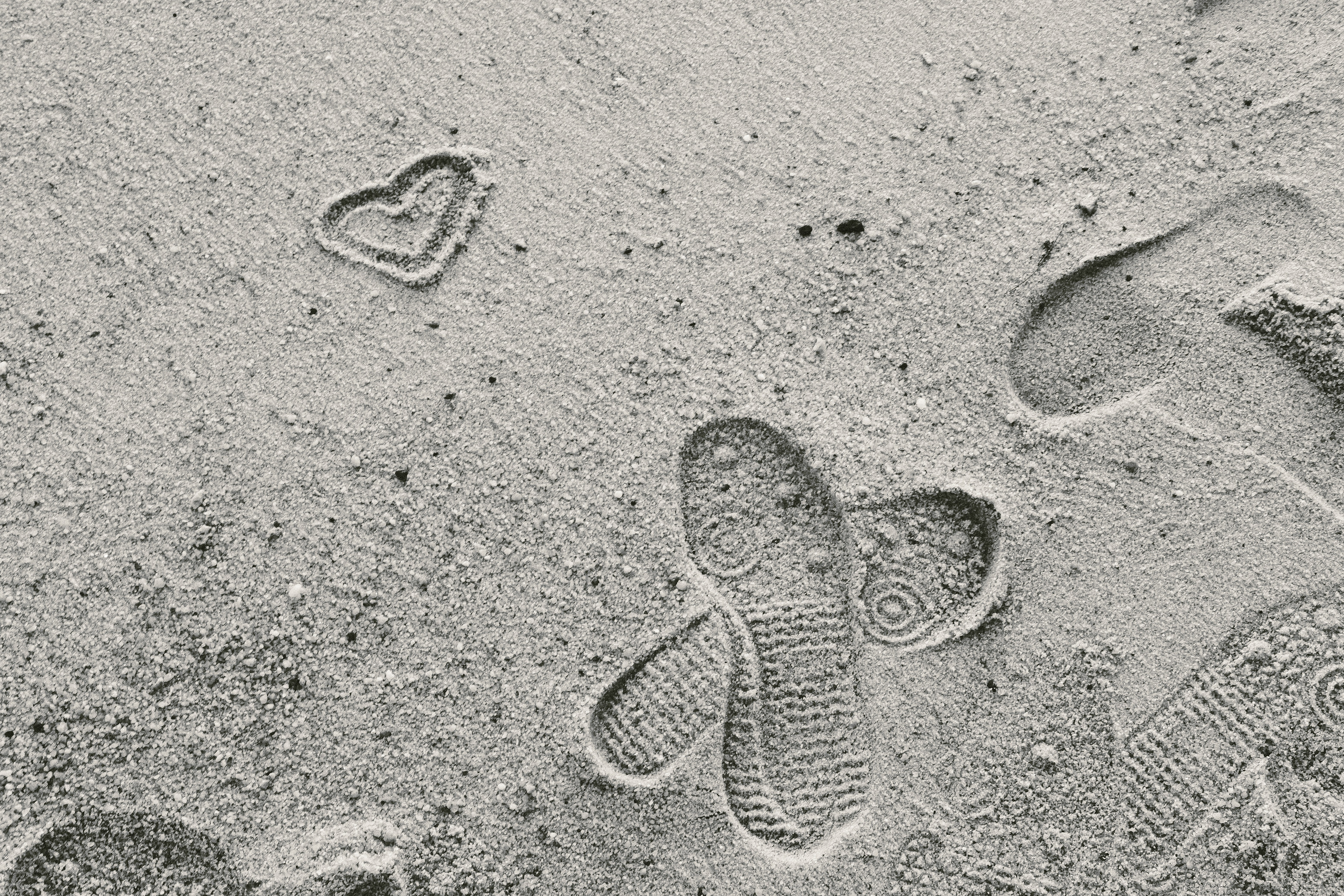Footprints and a heart shape etched into sandy terrain, capturing a moment of connection.