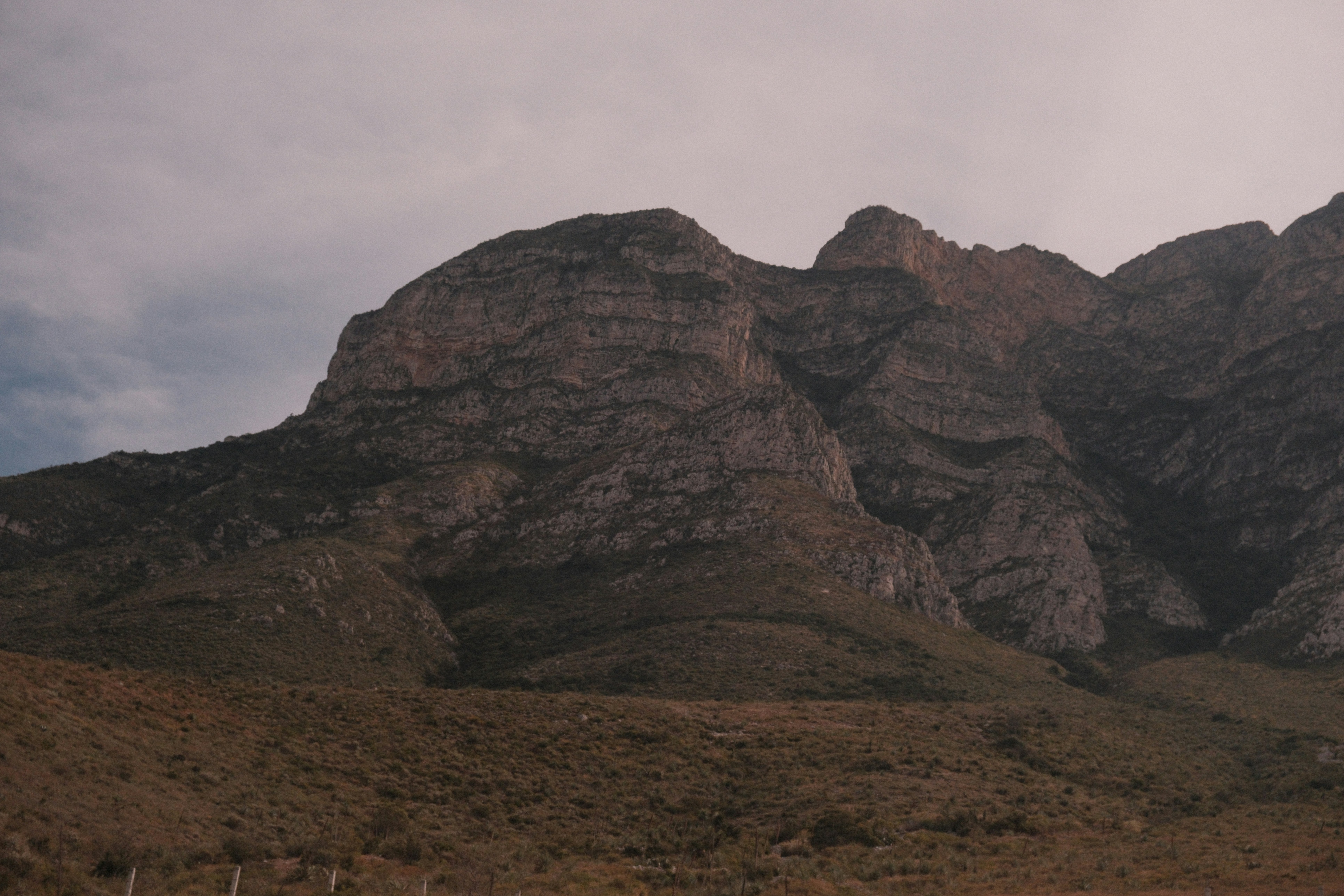 Rugged mountain range beneath a cloudy sky in muted daylight.