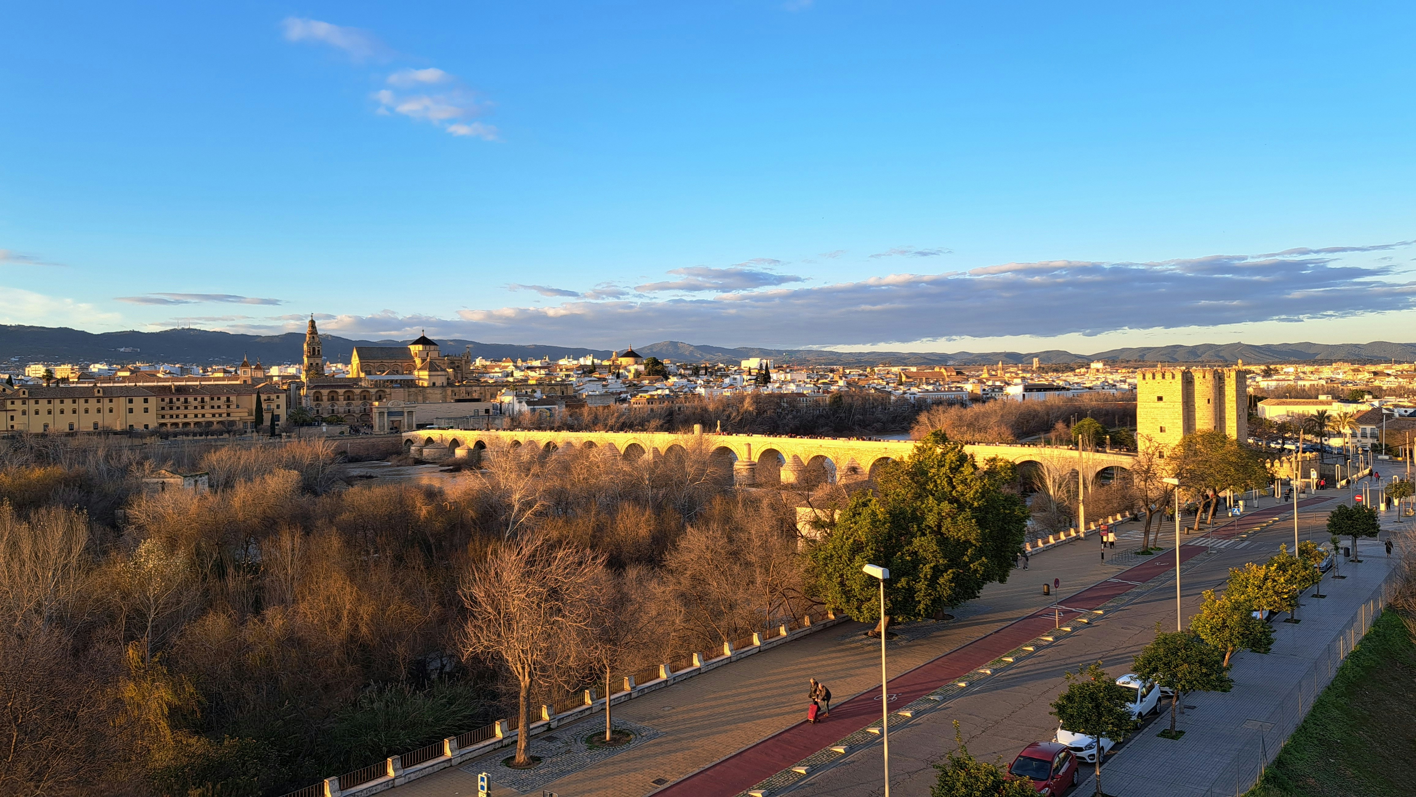 Mosque-cathedral and Roman bridge in Córdoba under a clear blue sky at sunset.