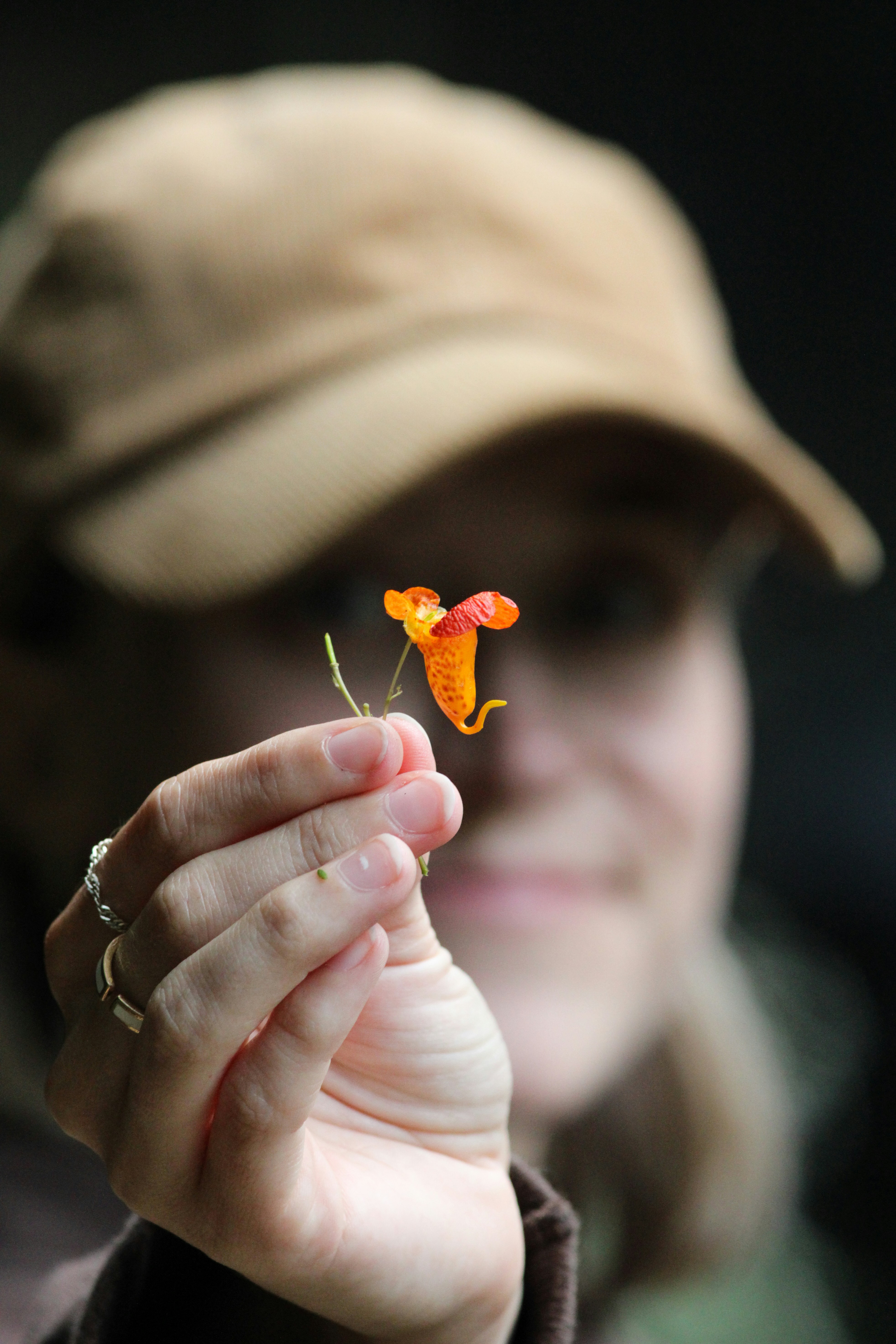 Tiny Ember Flower Held Close, Framed by a Soft-Focus Portrait