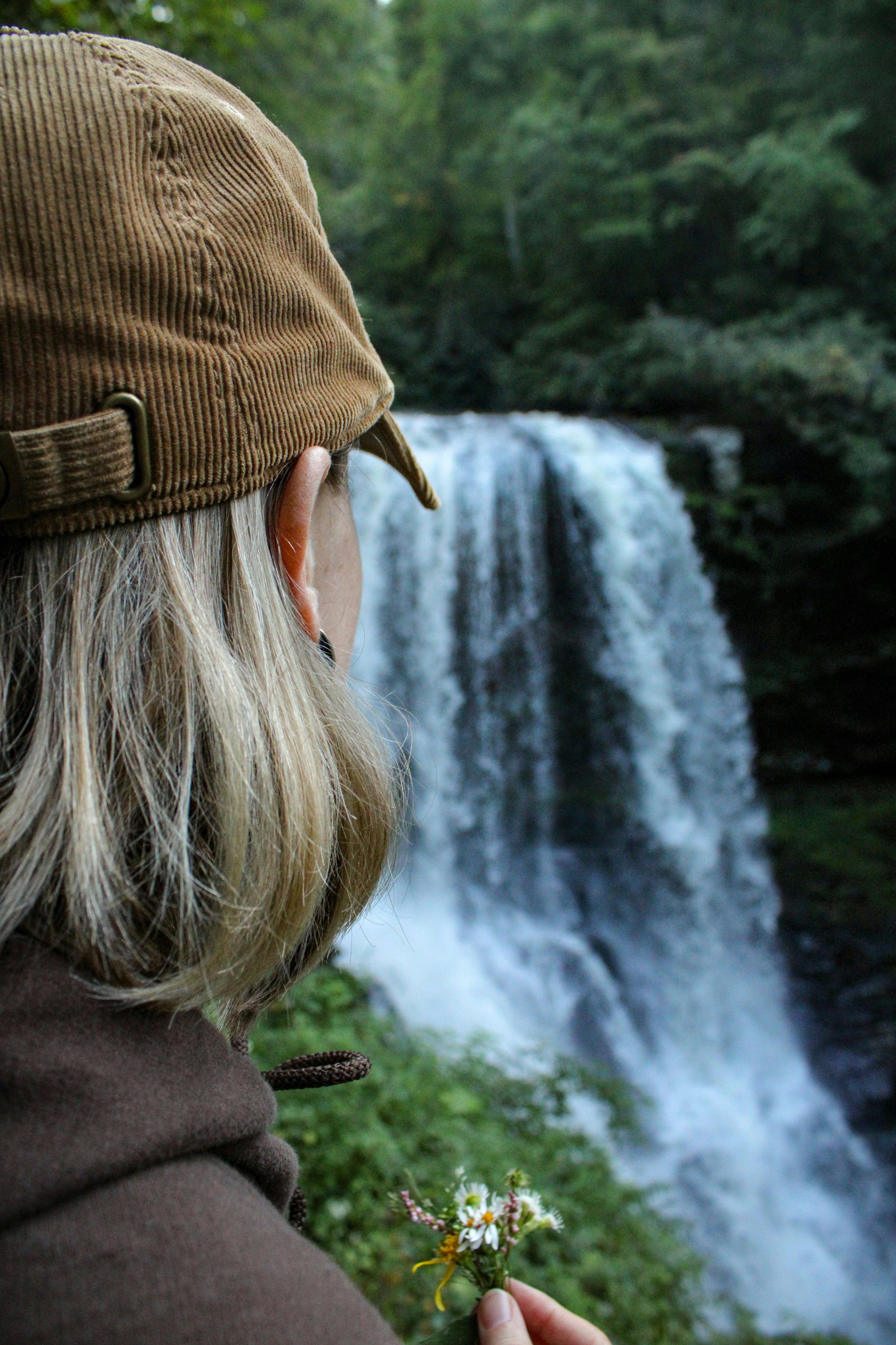 Beside the Veil: a traveler studies a waterfall from the edge of the frame