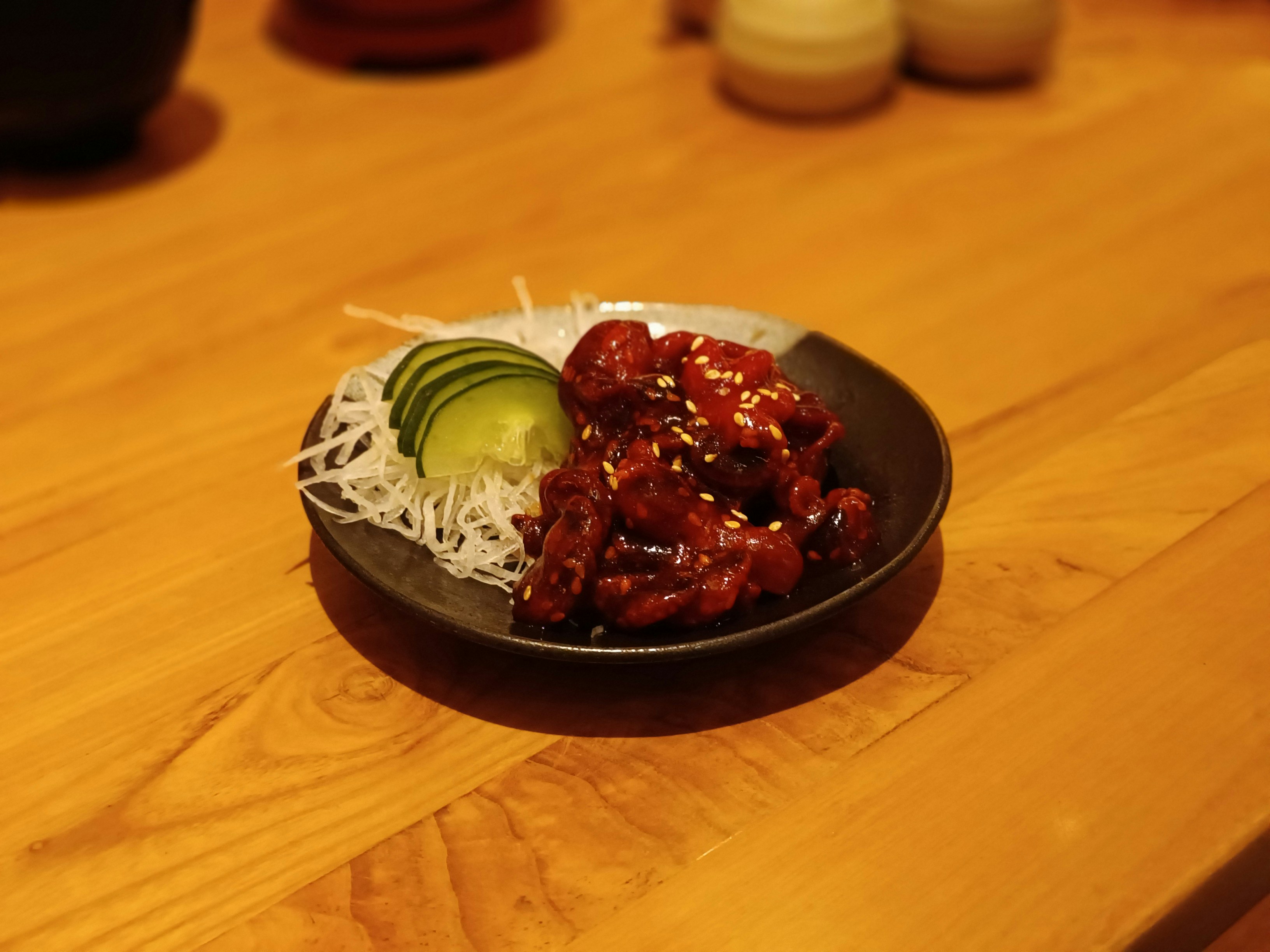 Chuka Idako with shredded daikon and cucumber on a wooden table.