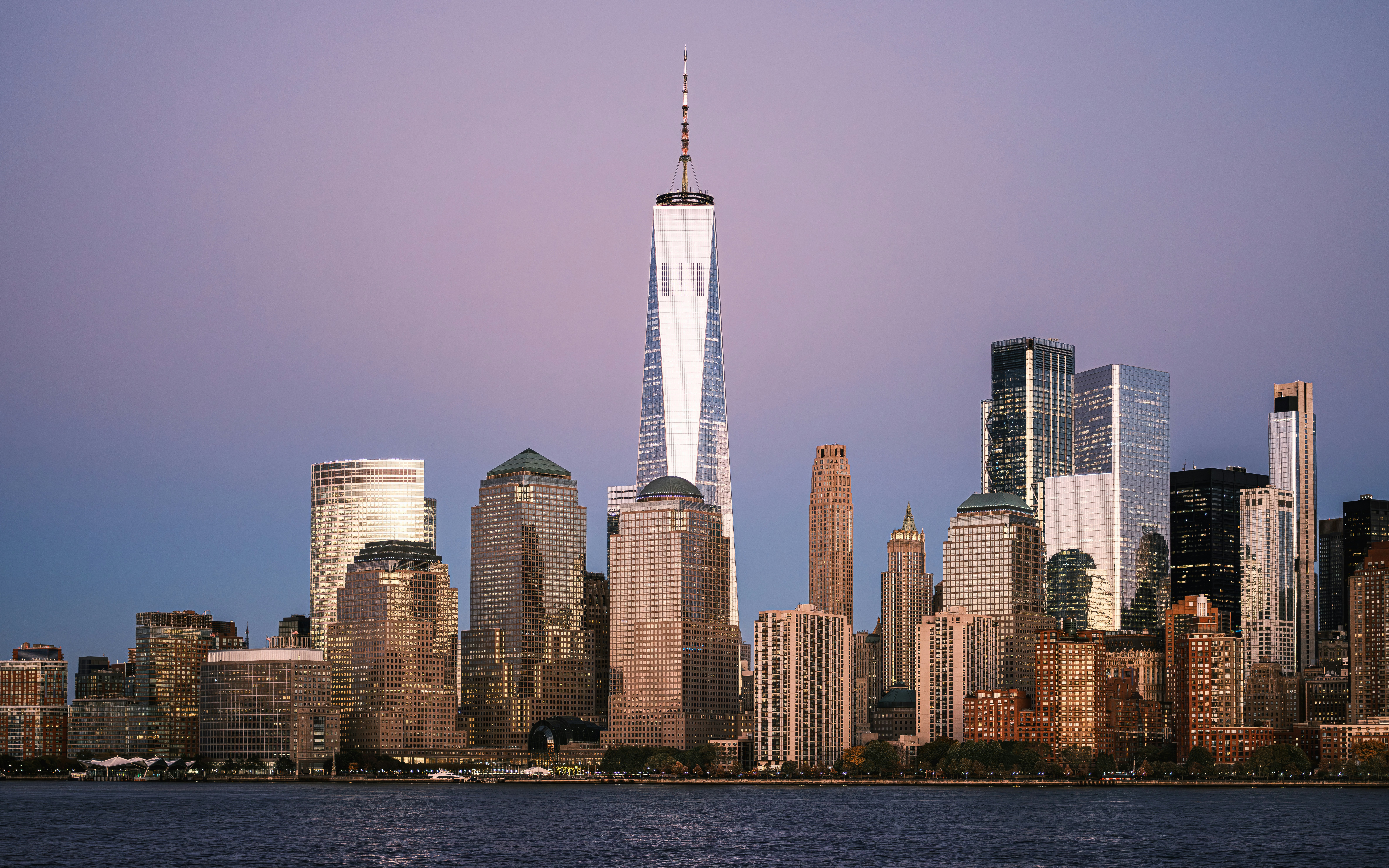 New York City skyline at twilight with One World Trade Center reflecting soft evening light.