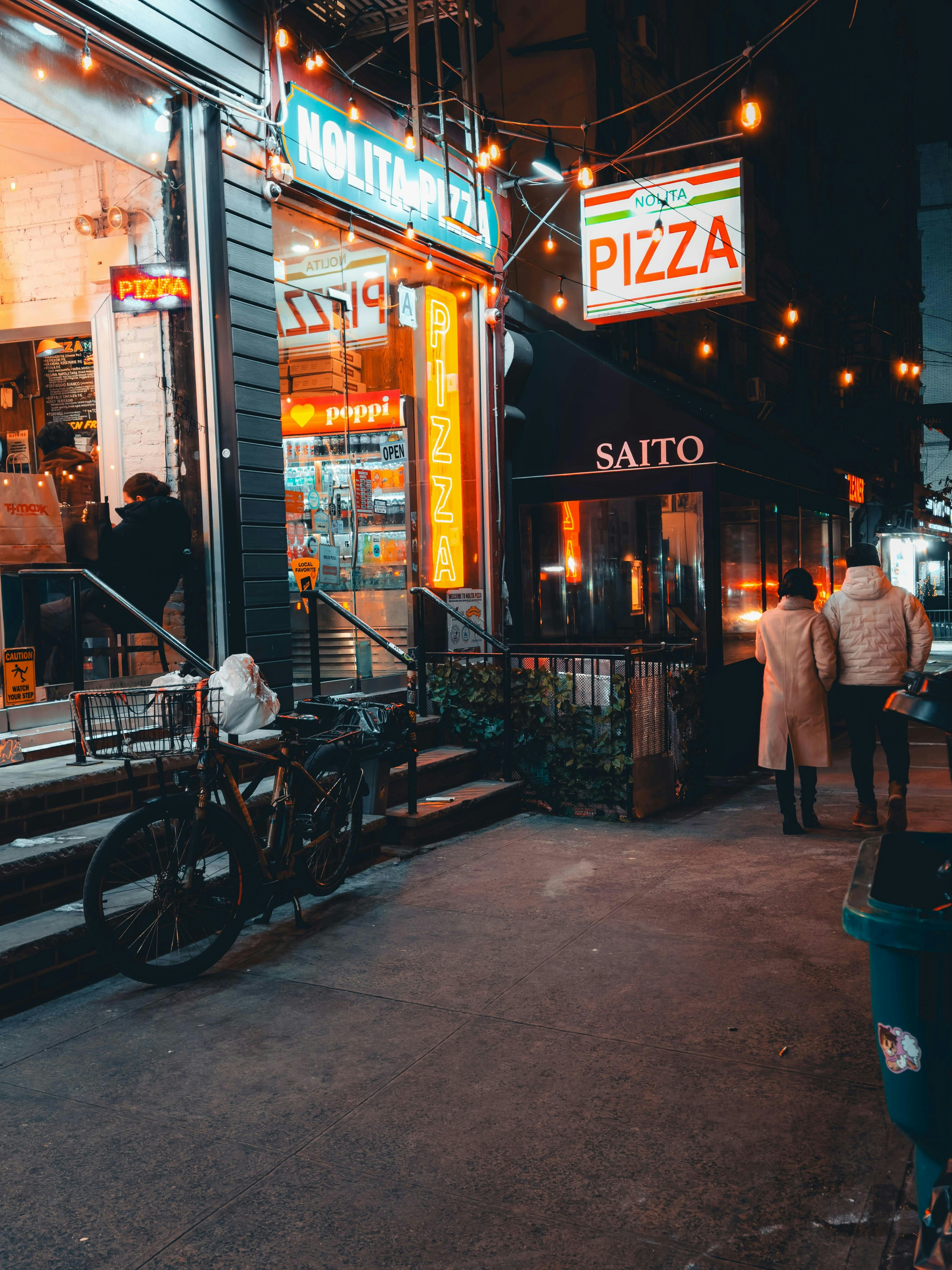 A group of people standing outside of a pizza shop photo – Free City ...