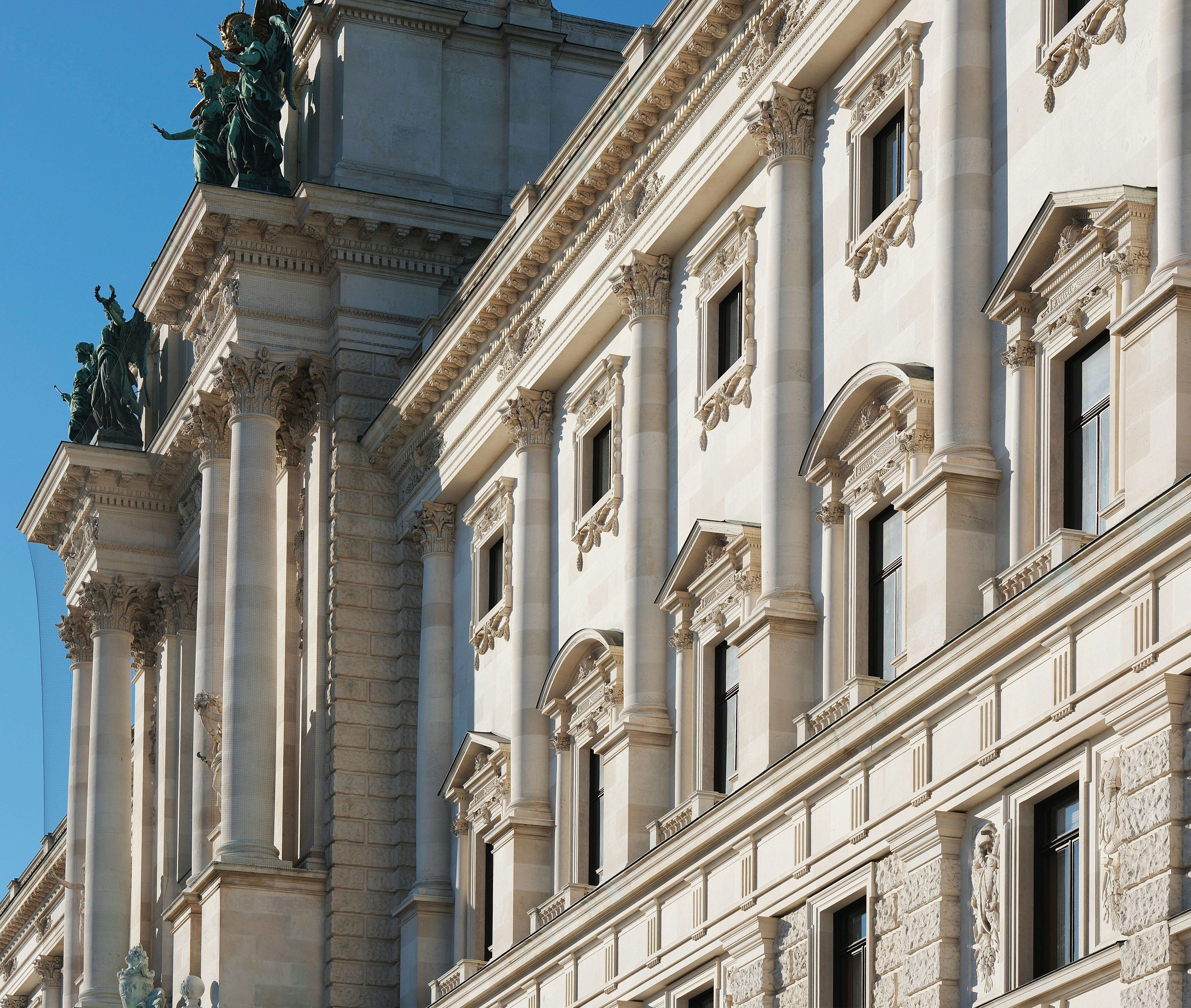 Sunlit facade of Hofburg Palace with intricate sculptures and classical columns.