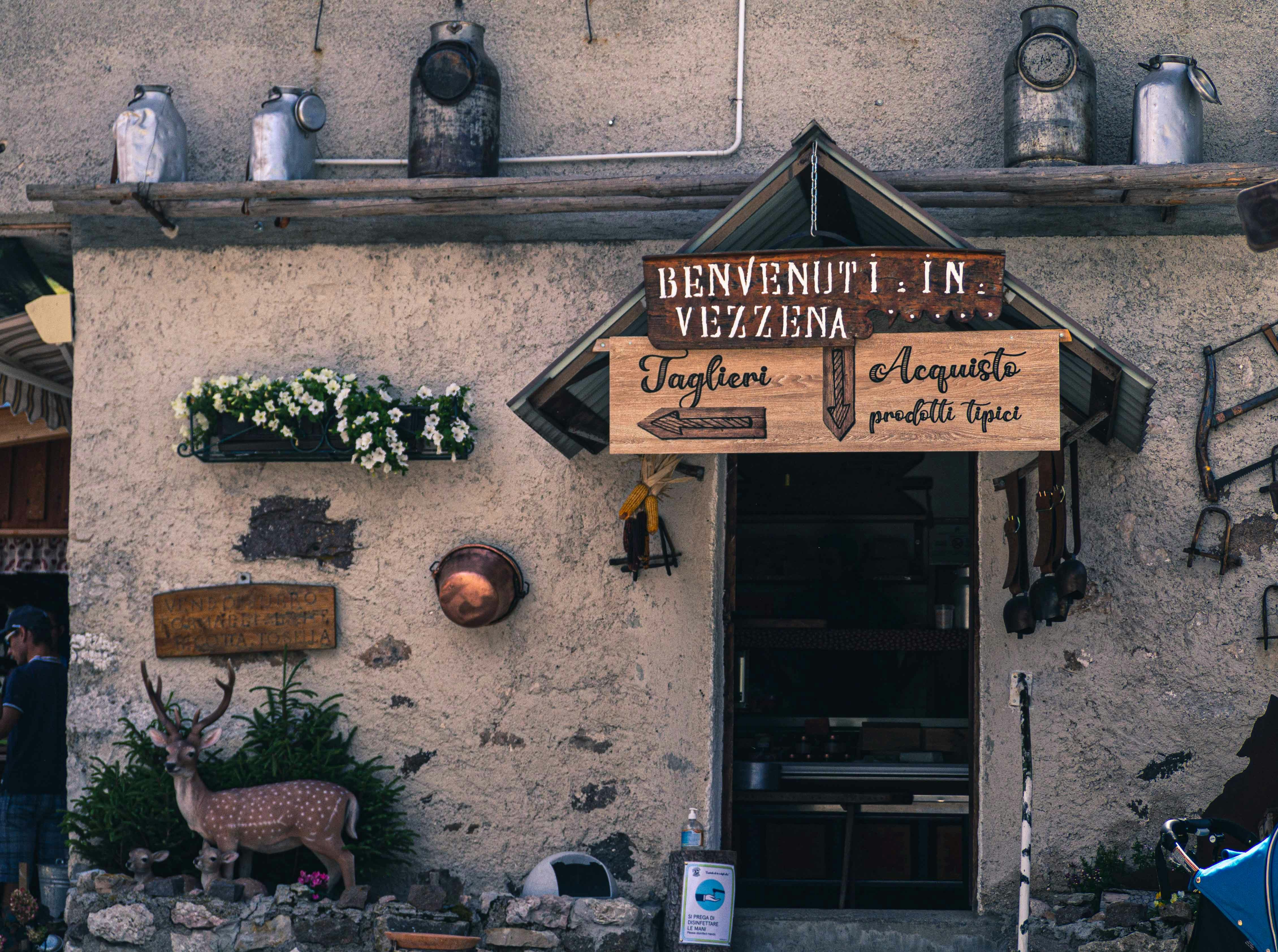 Rustic entrance adorned with vintage items and a welcoming sign in a quaint mountain setting.