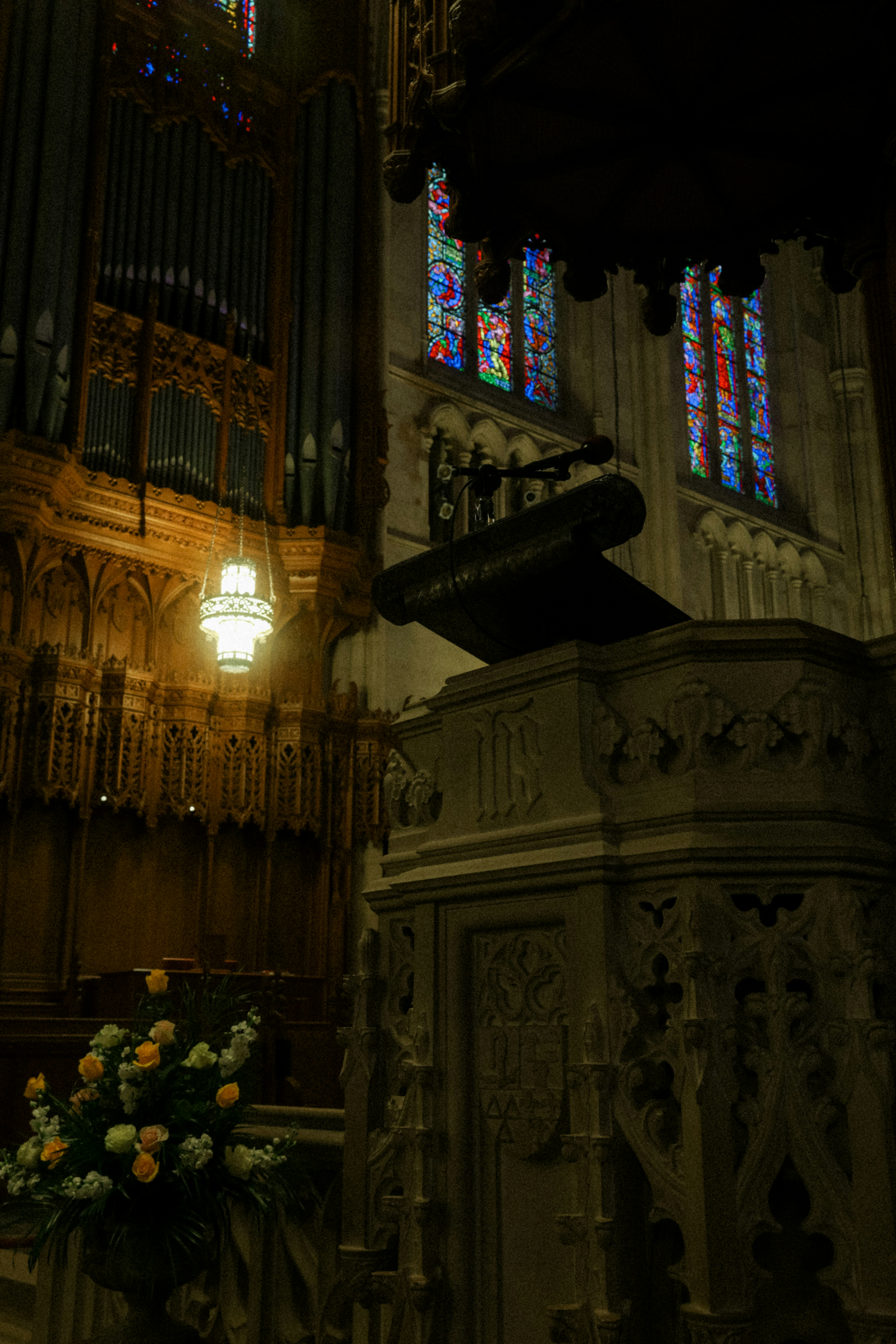 Dim Cathedral Niche: Stained Glass Illuminated by Ornate Pulpit Lantern
