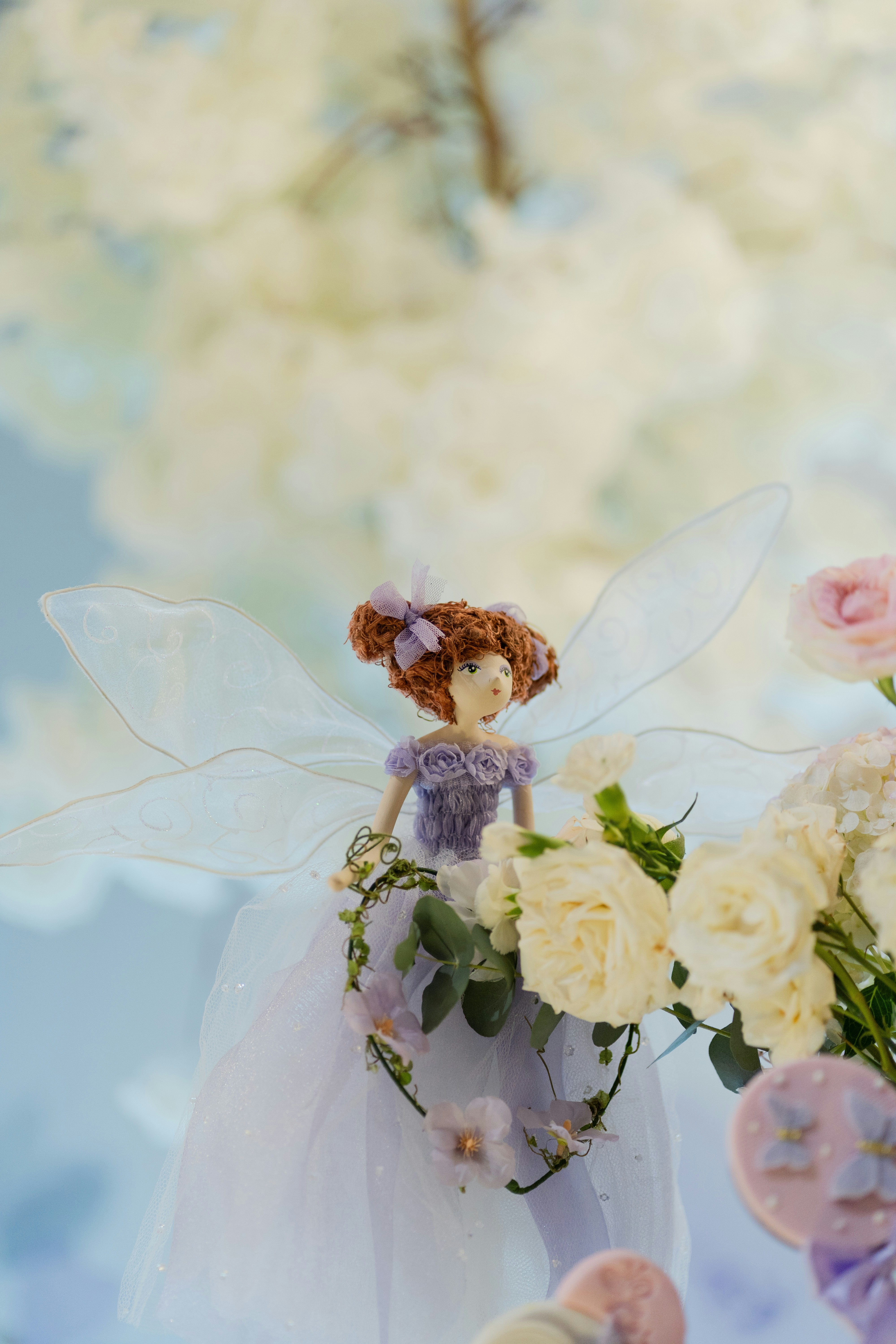 Lilac-Winged Fairy Doll Amid Cream Roses
