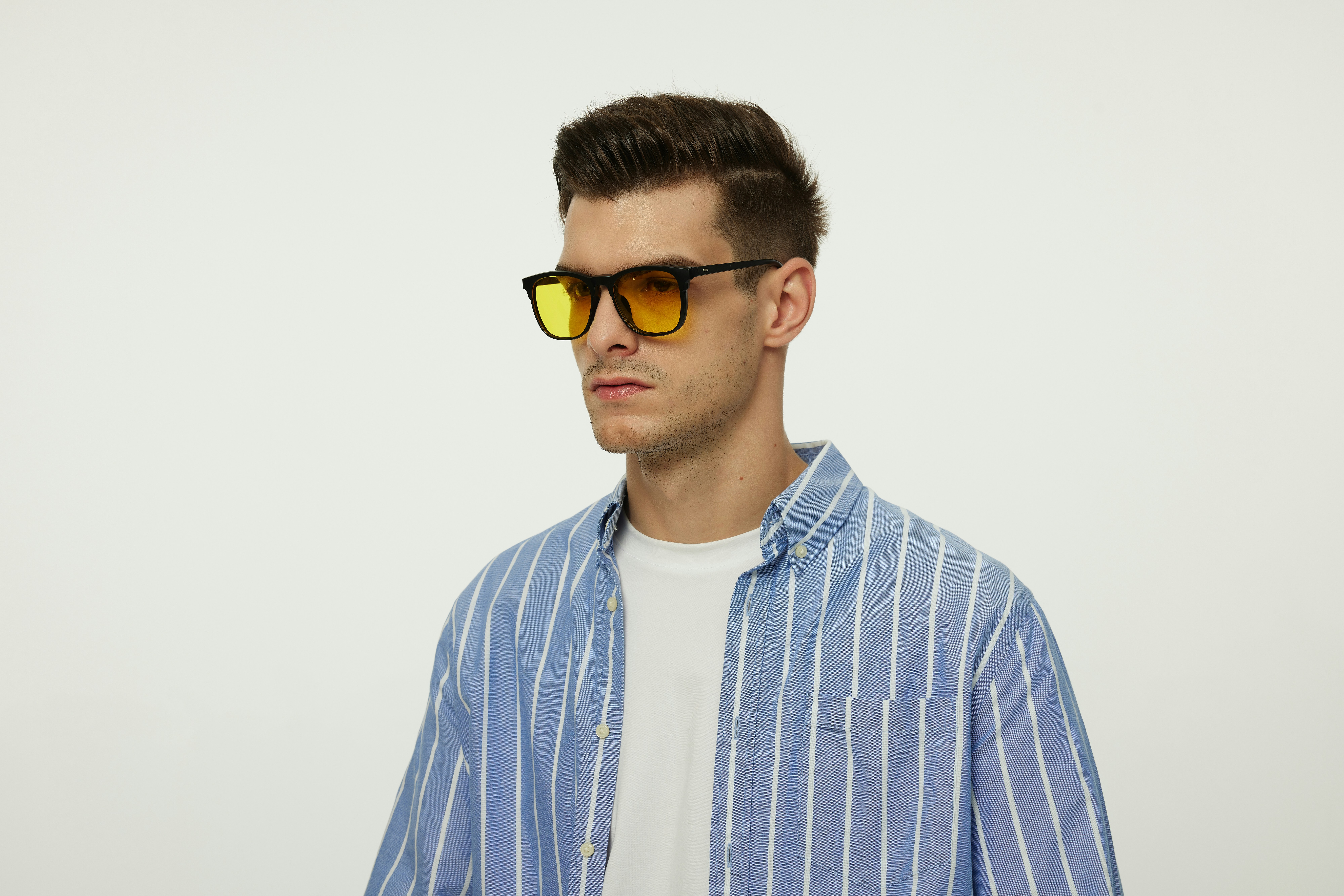 Person wearing black sunglasses with yellow-tinted lenses, paired with a blue and white striped shirt against a plain background.