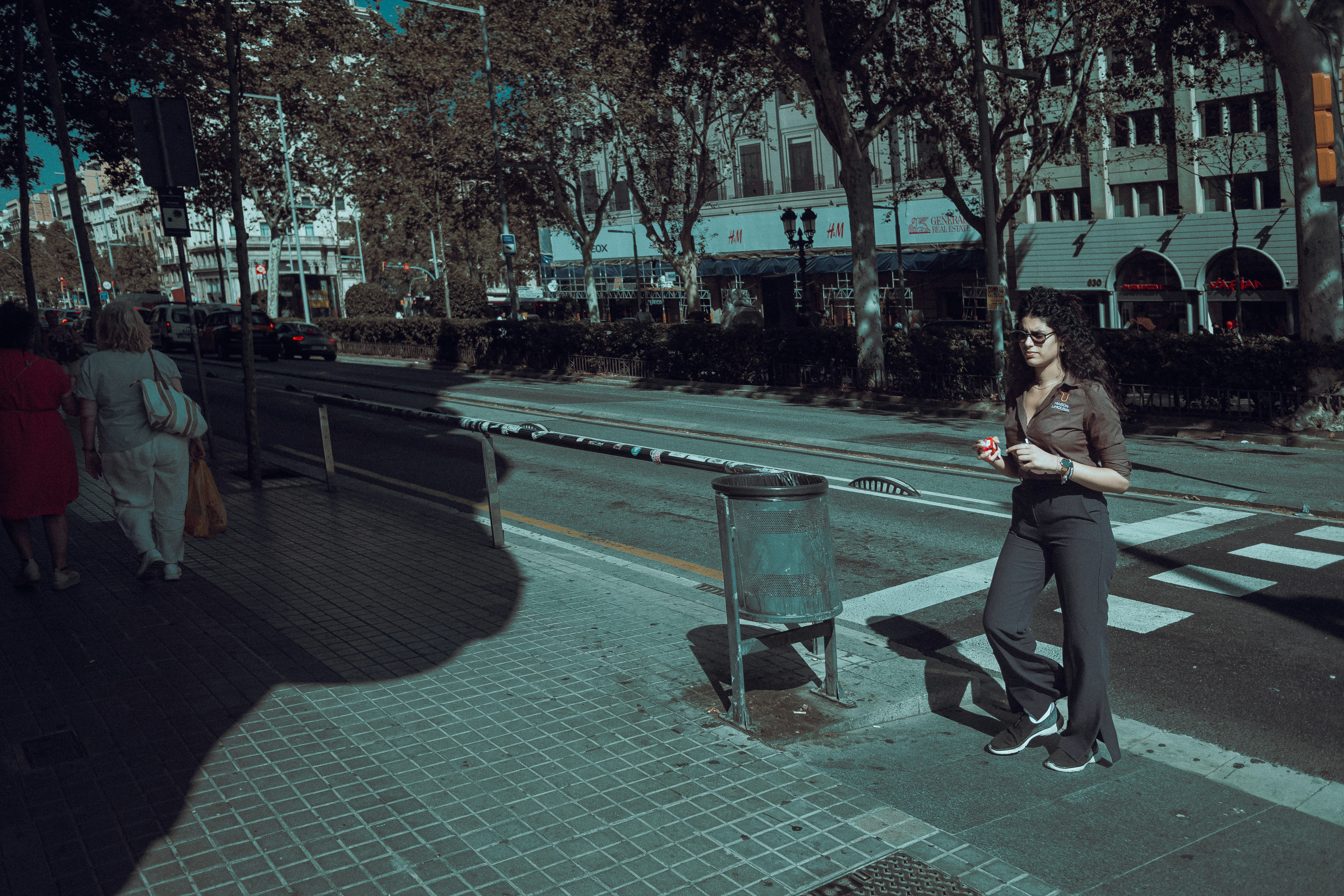 A woman running down a sidewalk next to a trash can photo – Free Car ...