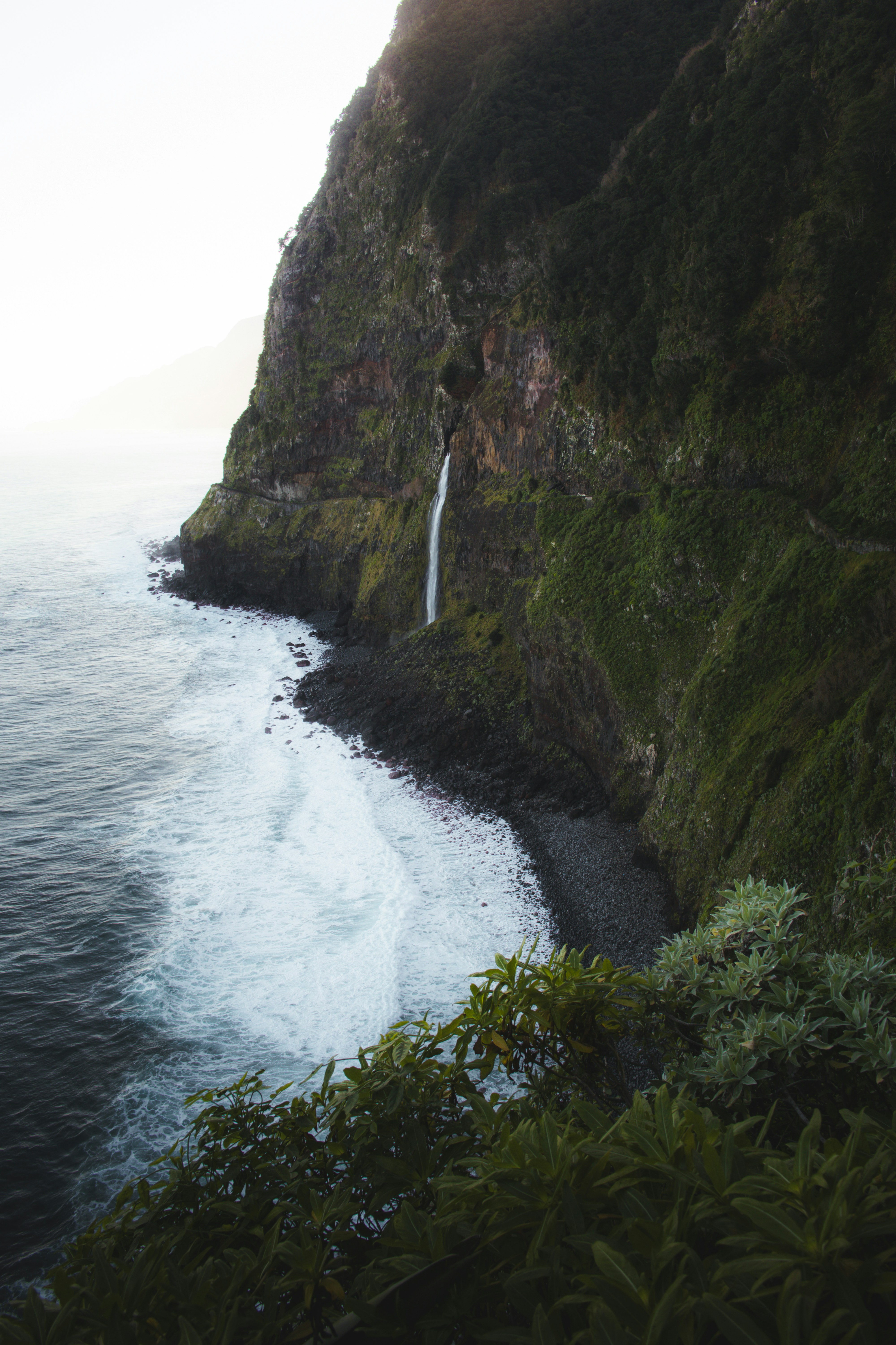 A waterfall on the side of a cliff next to the ocean photo – Free ...