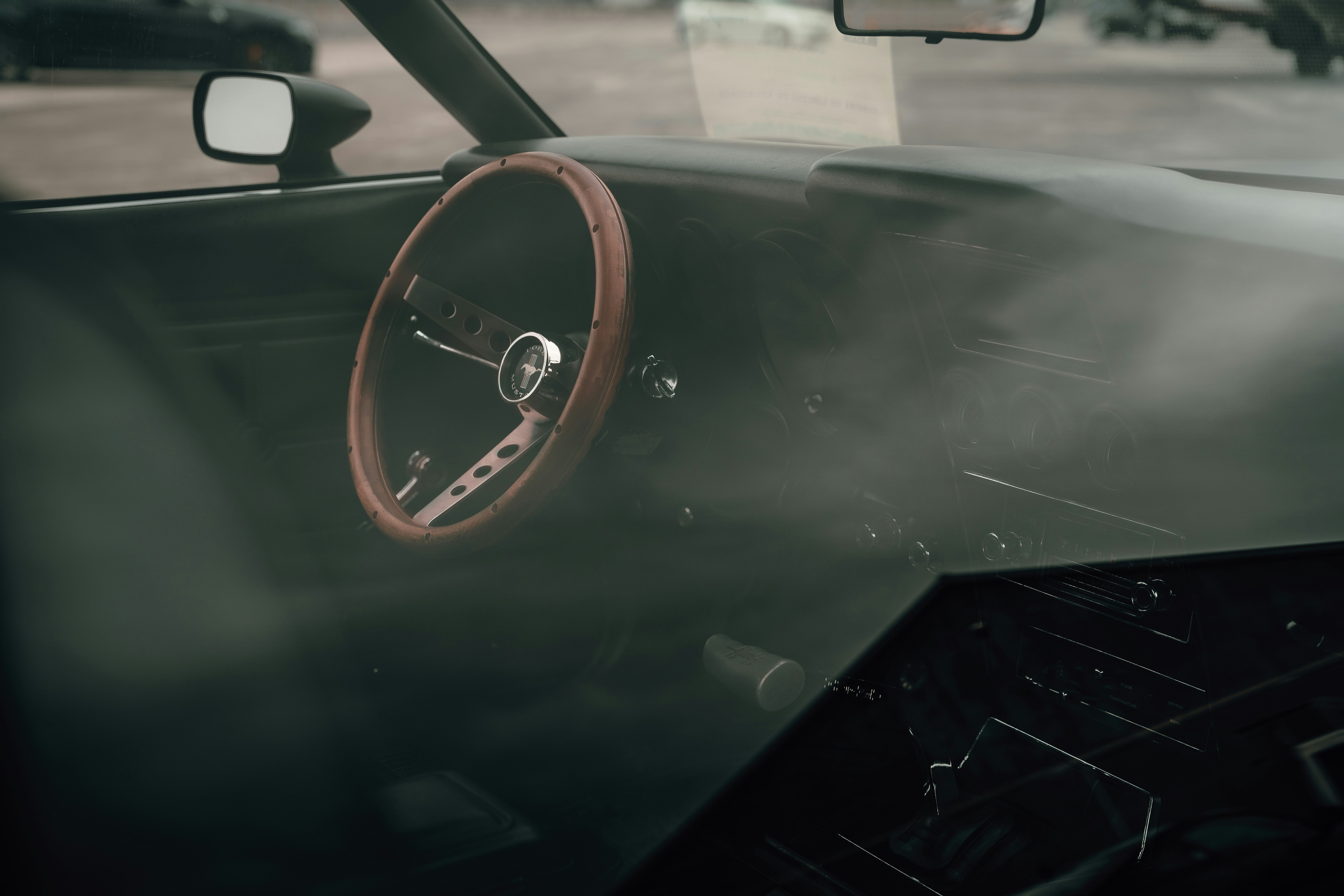 Classic car interior with a wooden steering wheel and retro dashboard.