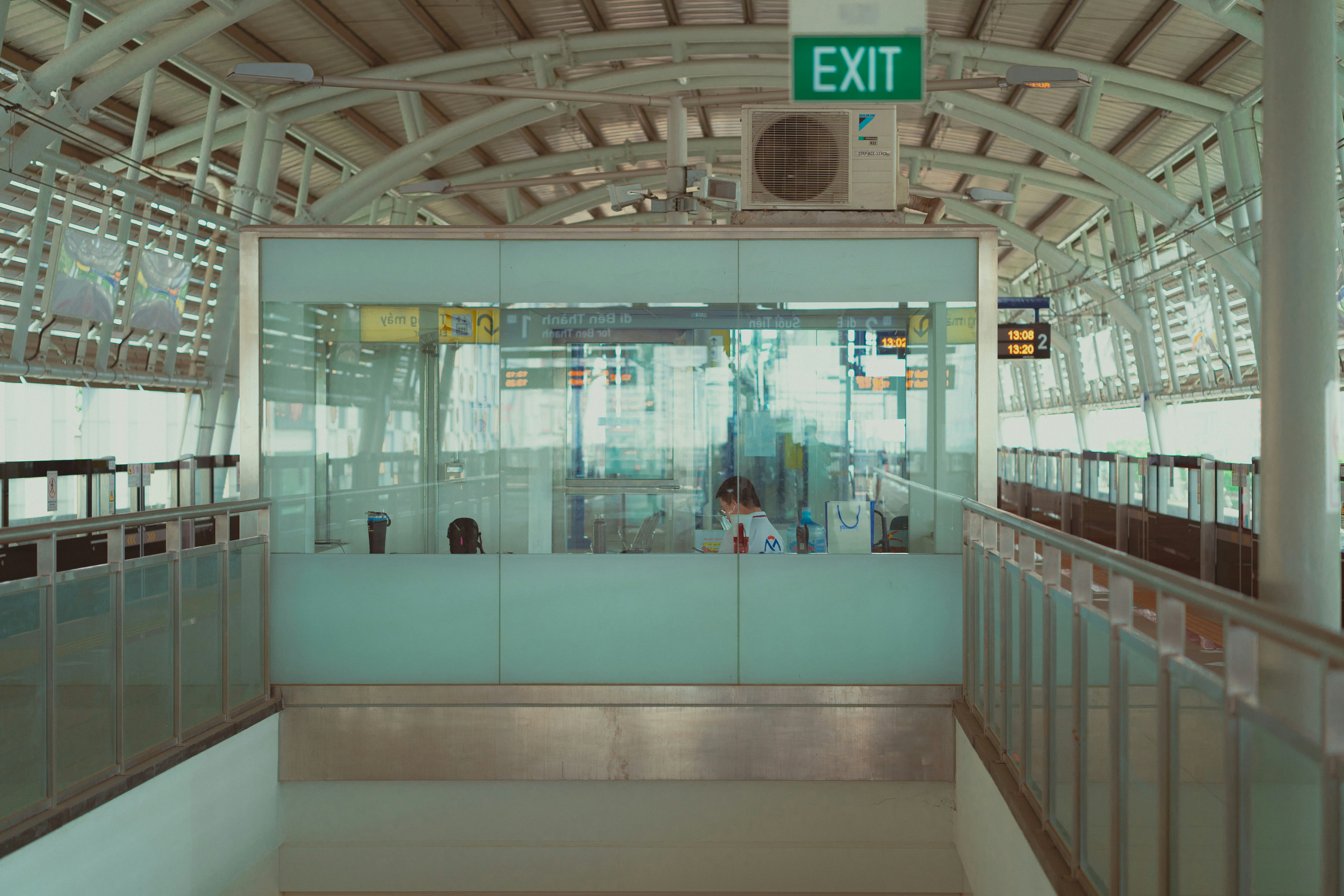 A train station with a green exit sign photo – Free Portrait Image on ...