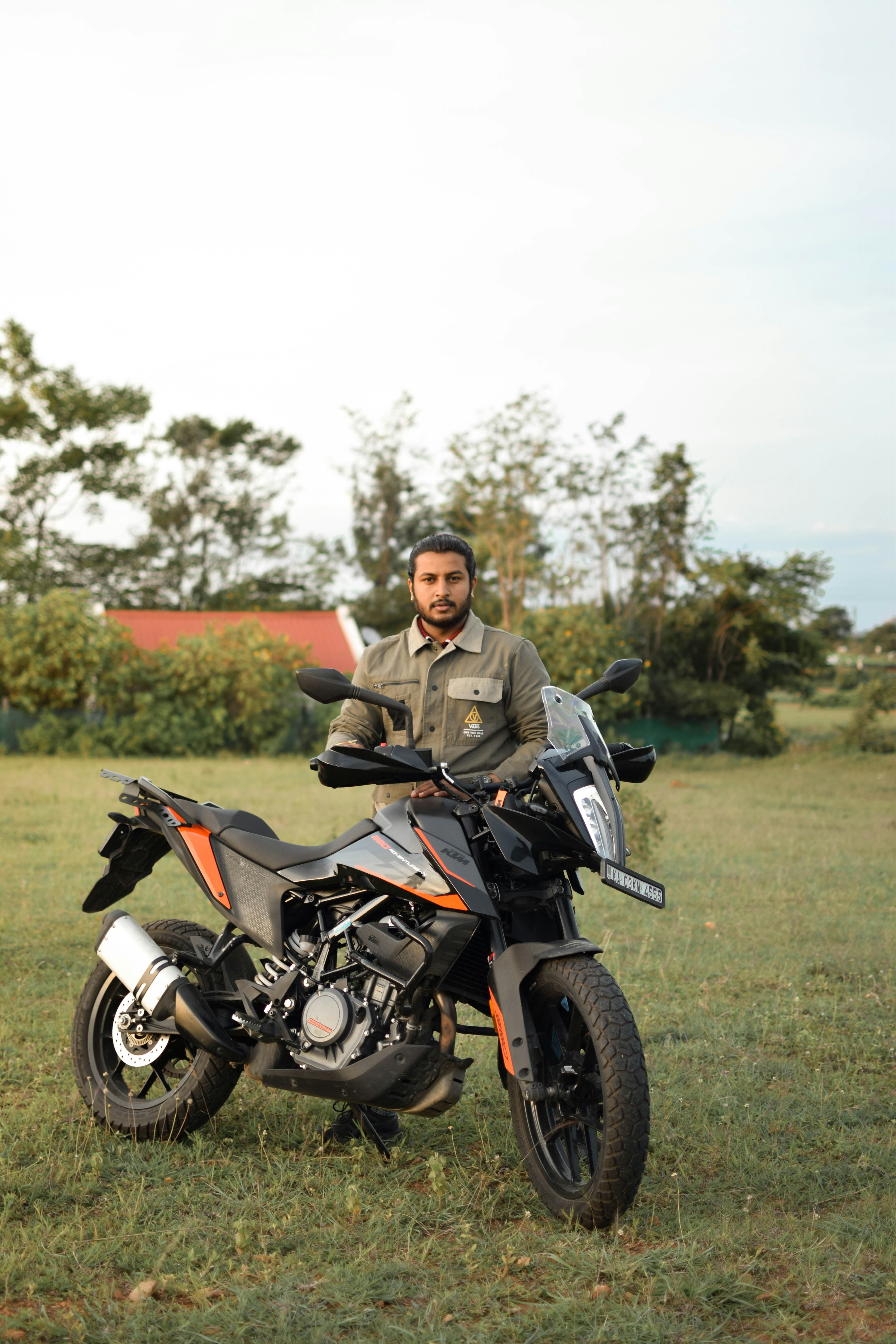 Sunlit Standstill: A Rider and His KTM-Style Dual-Sport in an Open Field