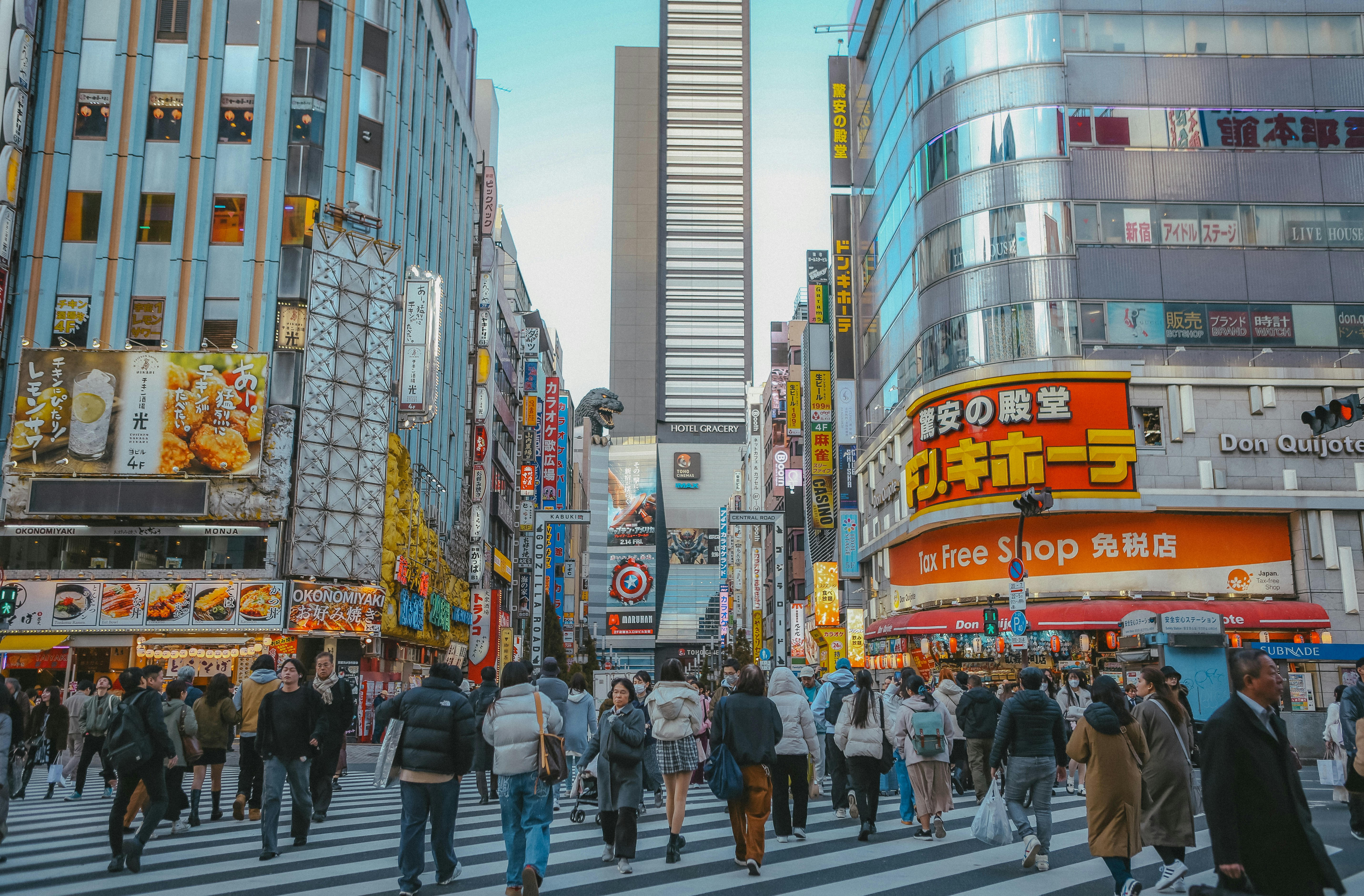 Crowded Shinjuku street with towering skyscrapers and vibrant storefronts.