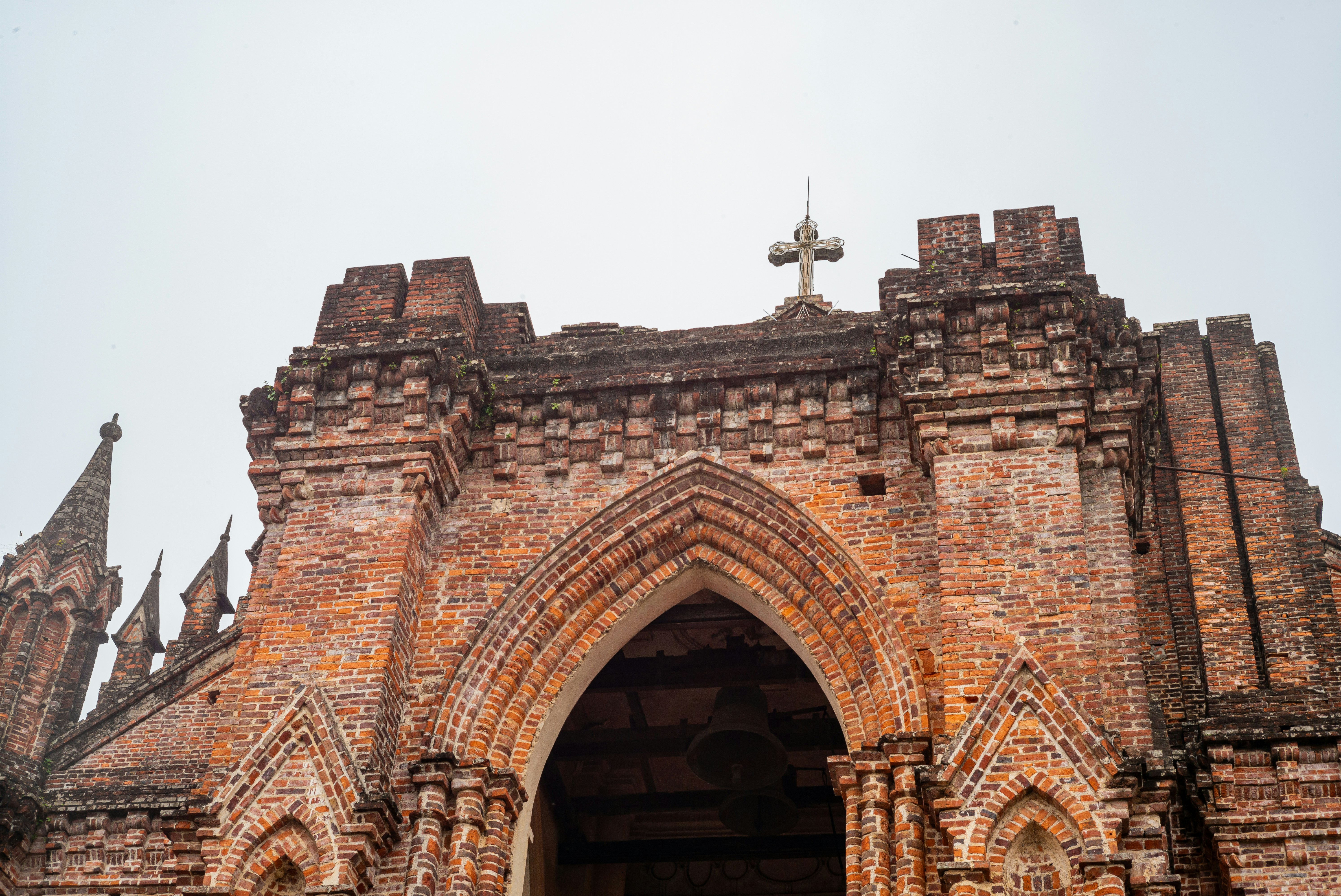 Brick Gothic Archway: Cross-Topped Doorway in Weathered Facade