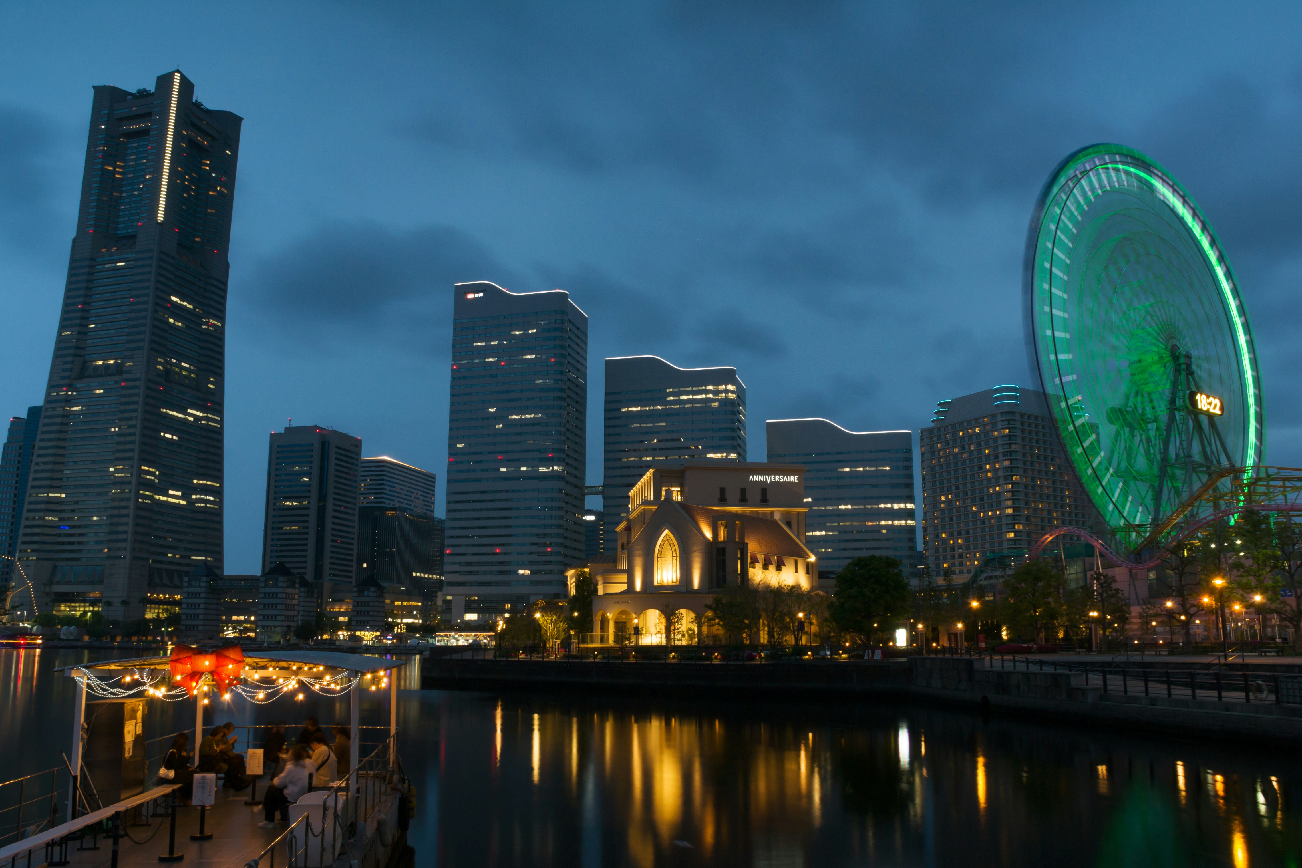 Cityscape of Yokohama featuring illuminated skyscrapers and a glowing Ferris wheel at dusk.