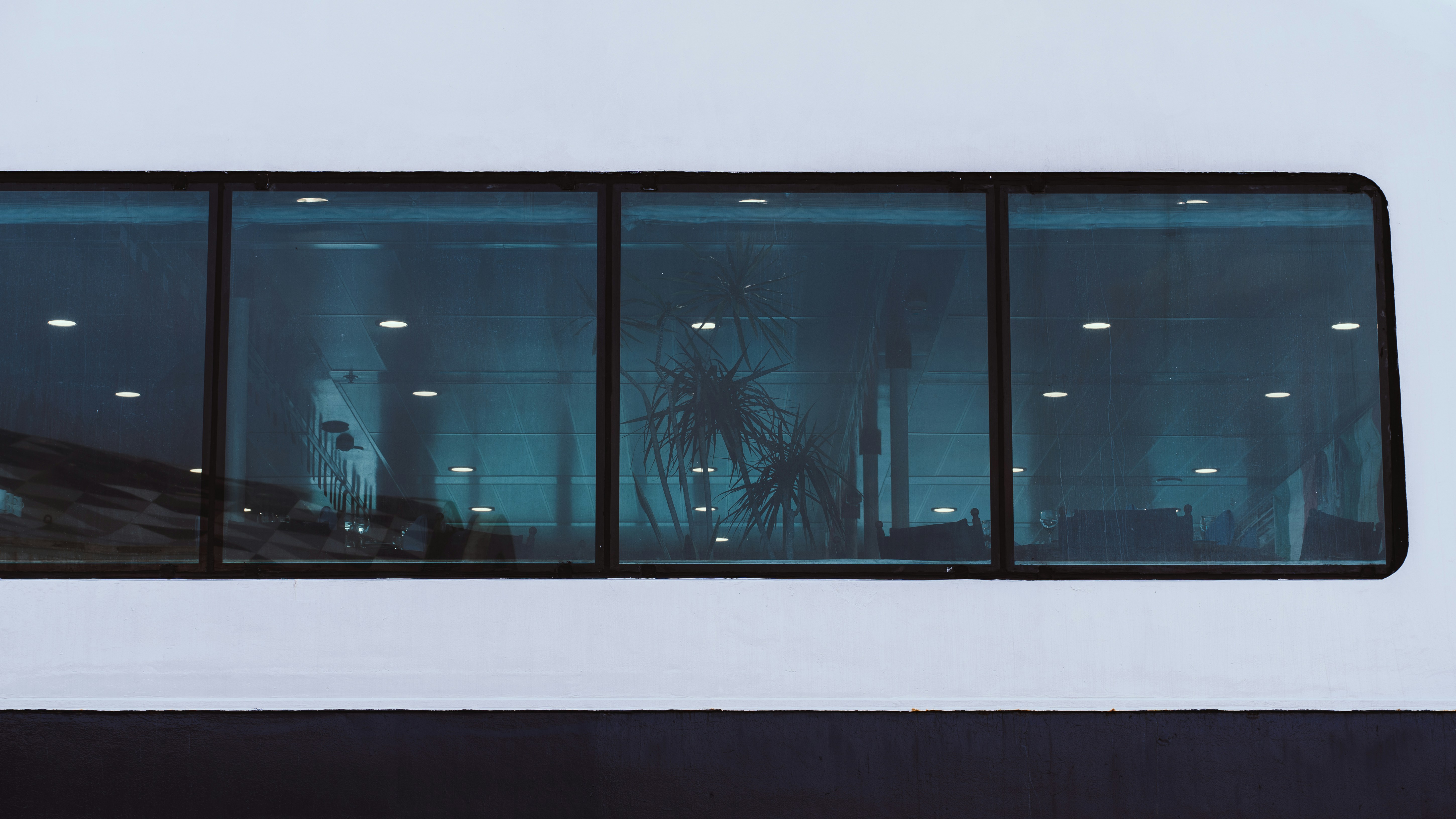 Rectangular glass windows reflecting interior lights and shadows, showcasing a minimalist architectural design.