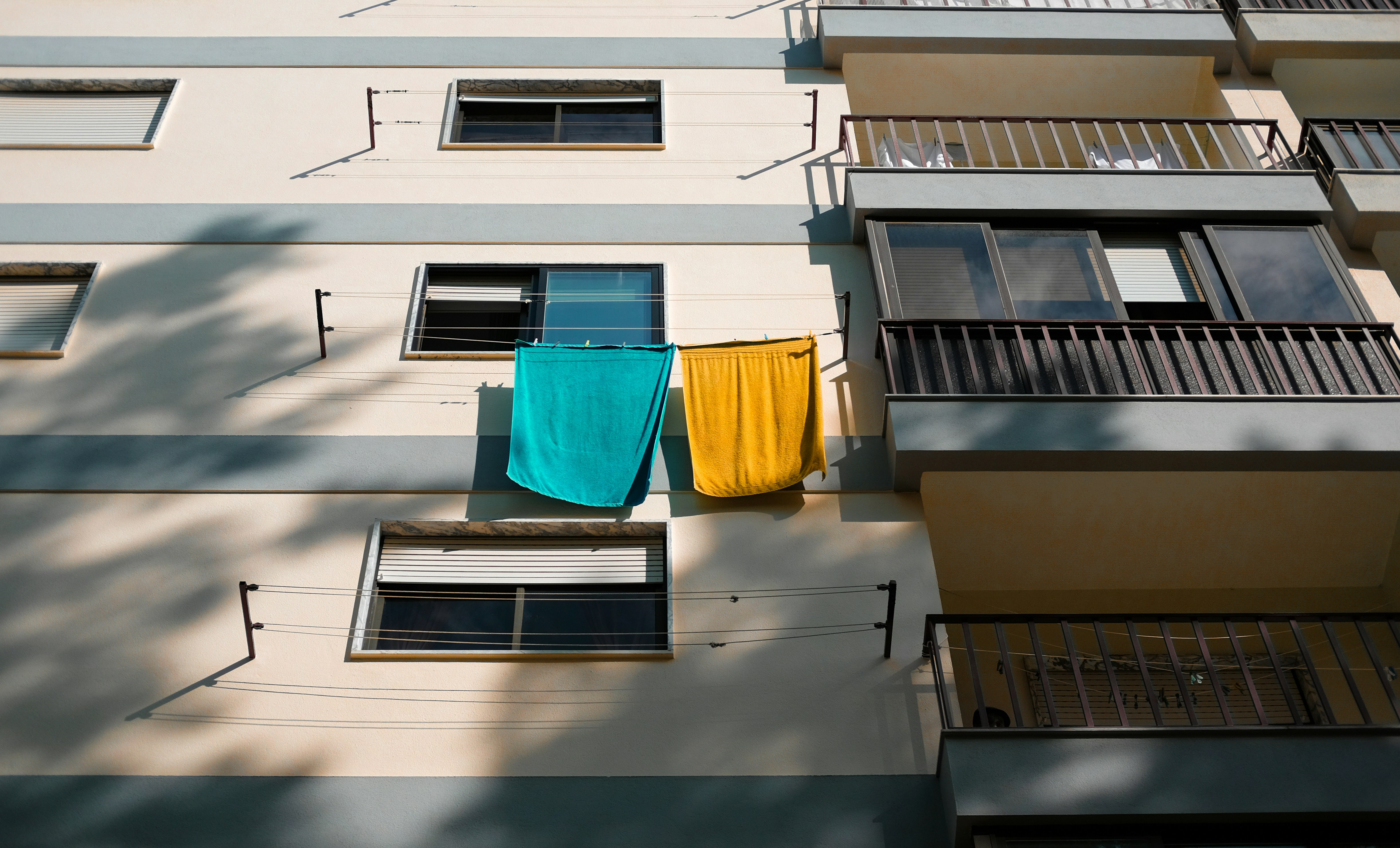 Color Echoes on a Concrete Façade: Turquoise and Amber Laundry Between Windows