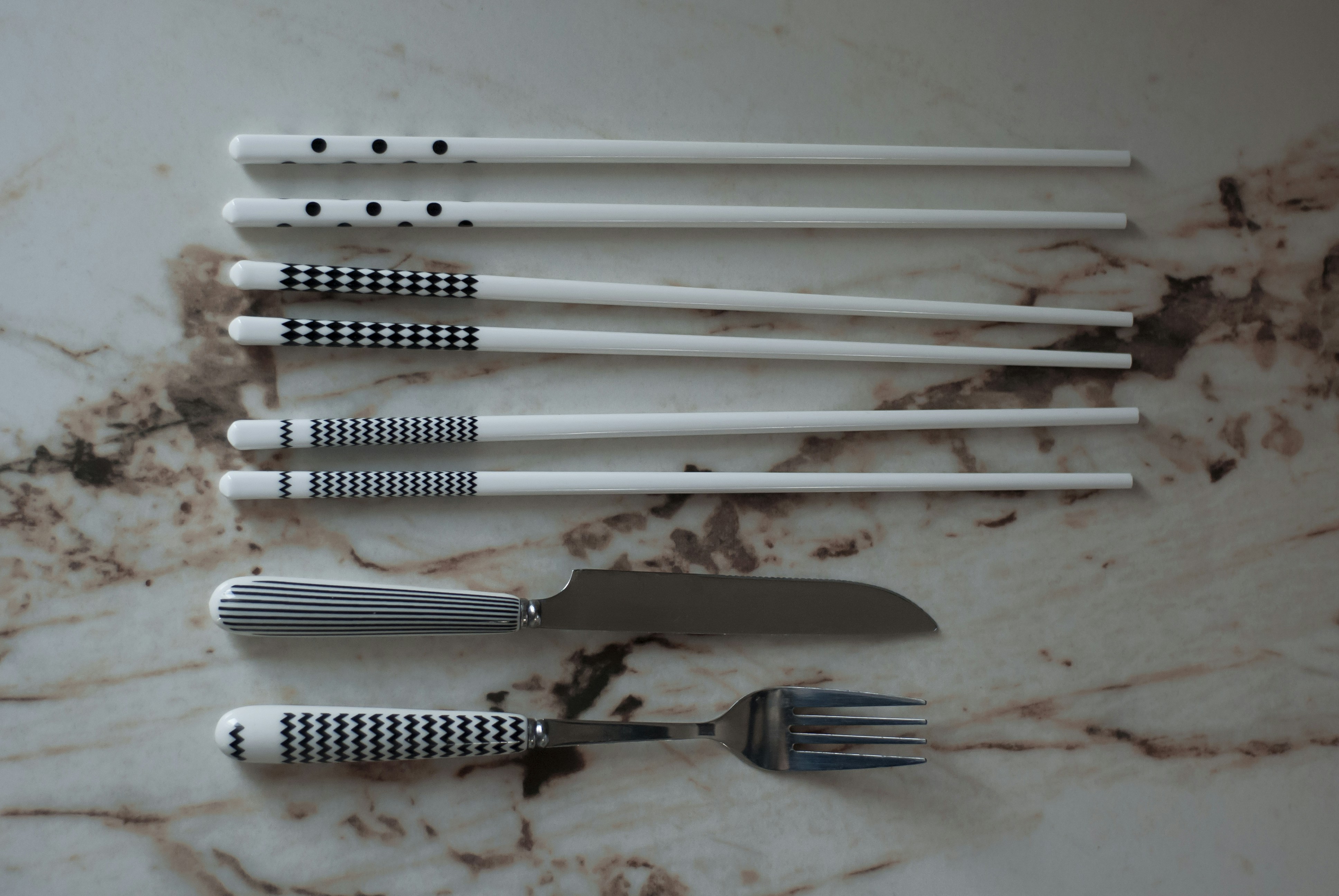Ceramic cutlery | A set of five forks and a knife on a marble counter