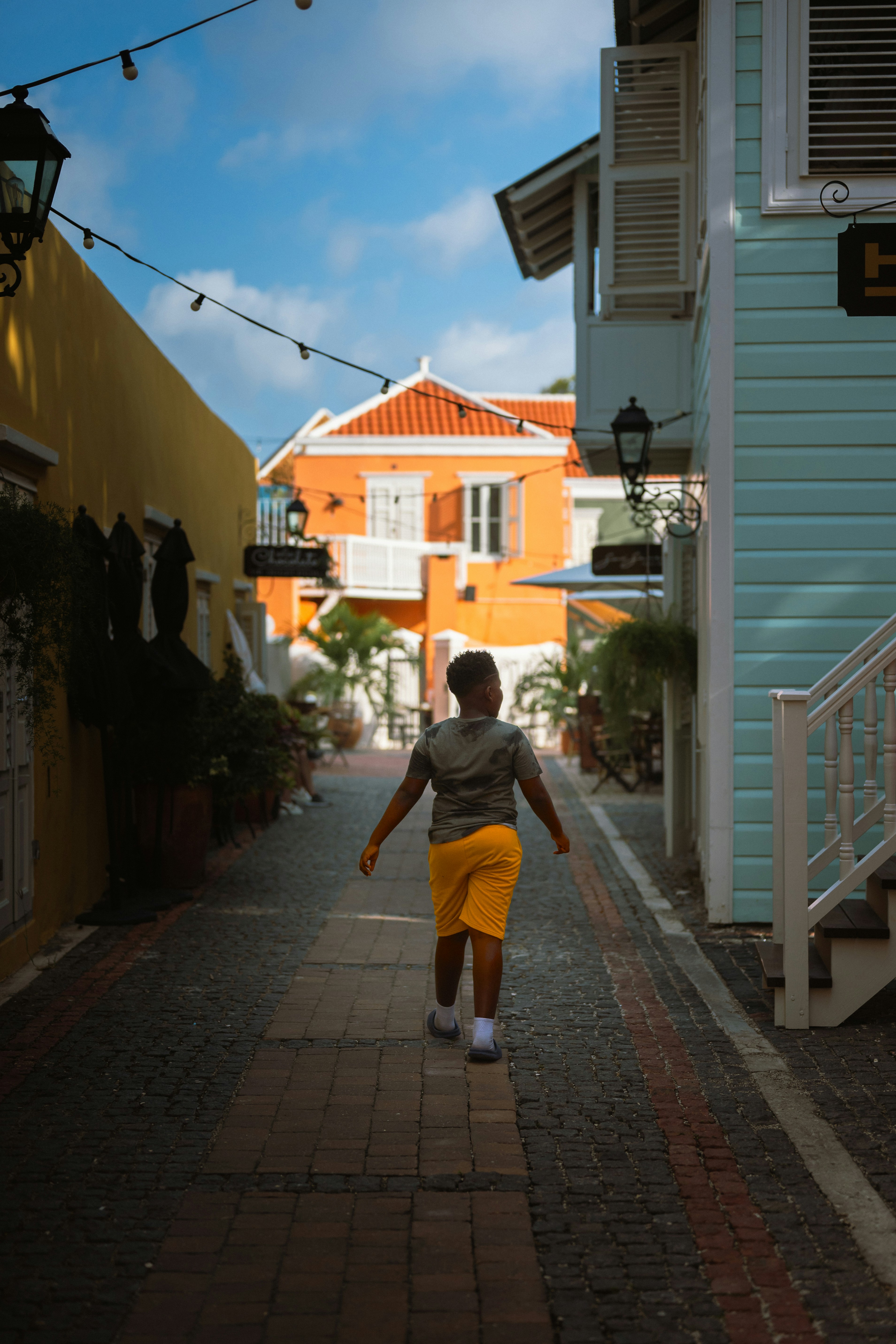 Stride Through a Colorful Coastal Alley Beneath String Lights