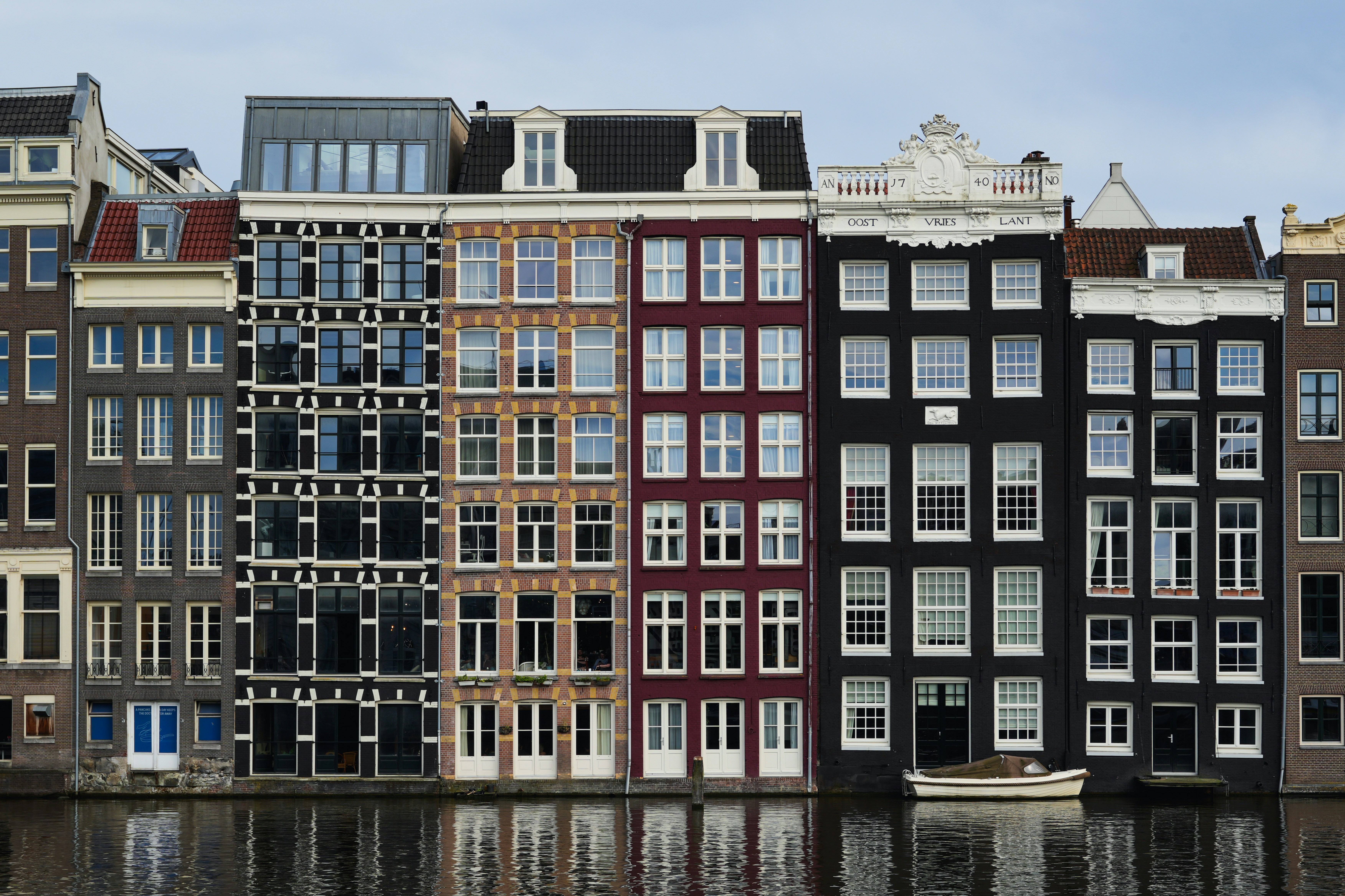 Colorful canal houses standing closely along the waterfront with reflections in the water.