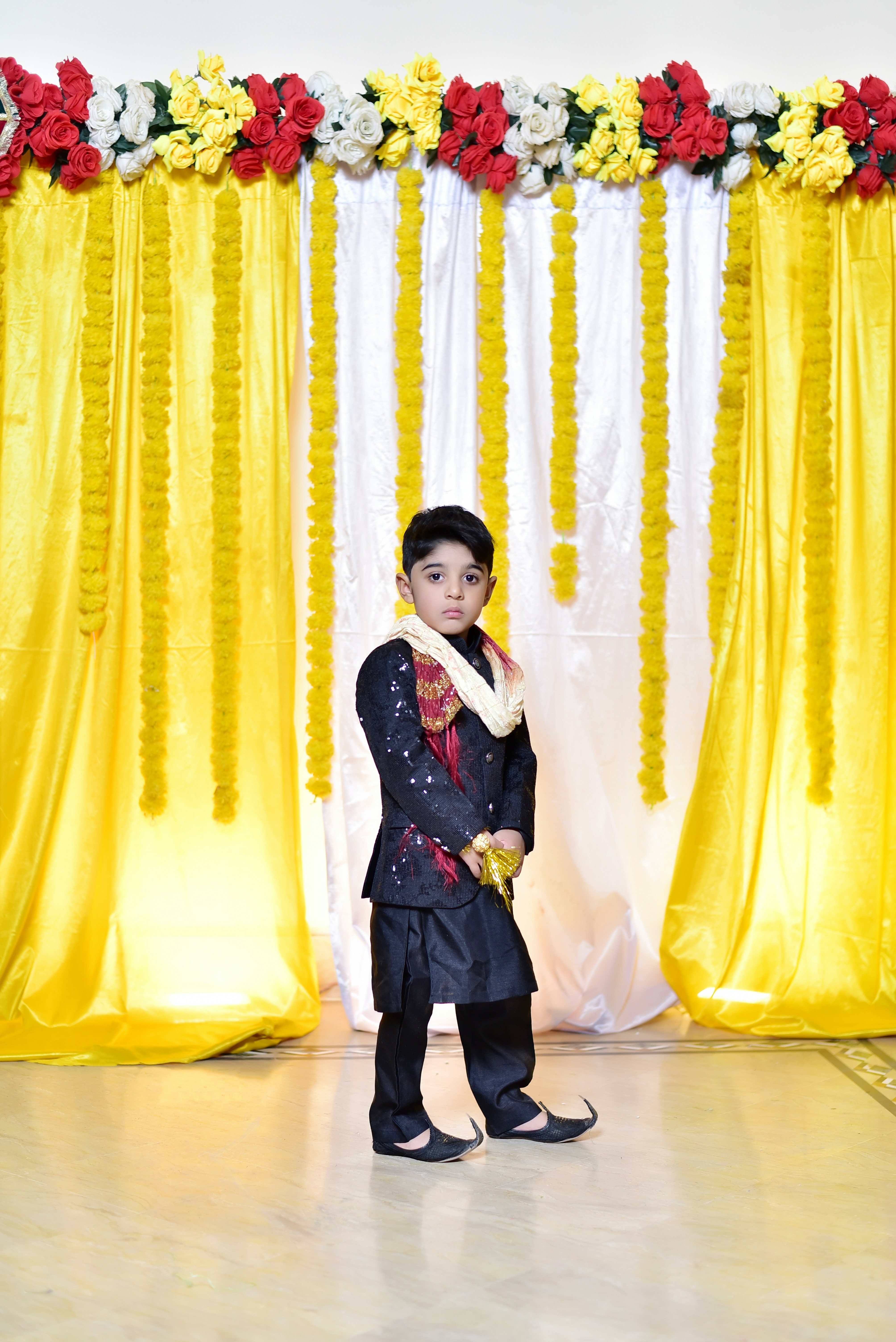 Pakistani Cultural wdding photoshoot Boy in black pakistani cultural wedding dresss | A young boy standing in front of a yellow curtain