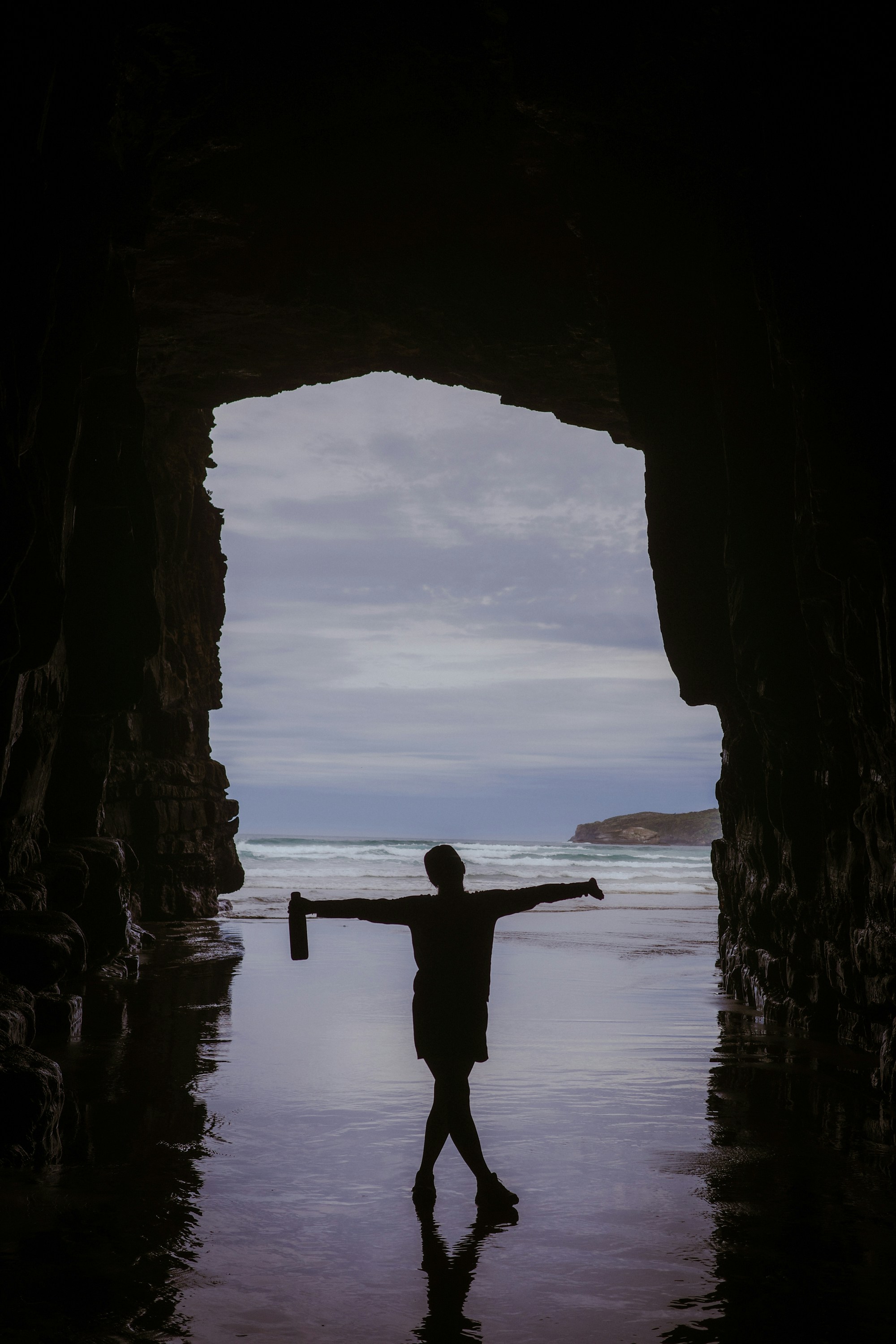Archway Silhouette: A Figure Framed by Sea and Stone
