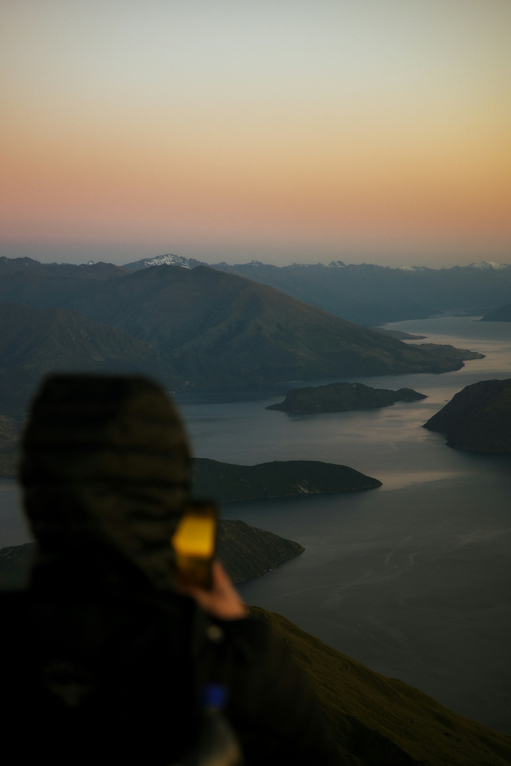 A person taking a picture of a sunset over a body of water photo – Free ...