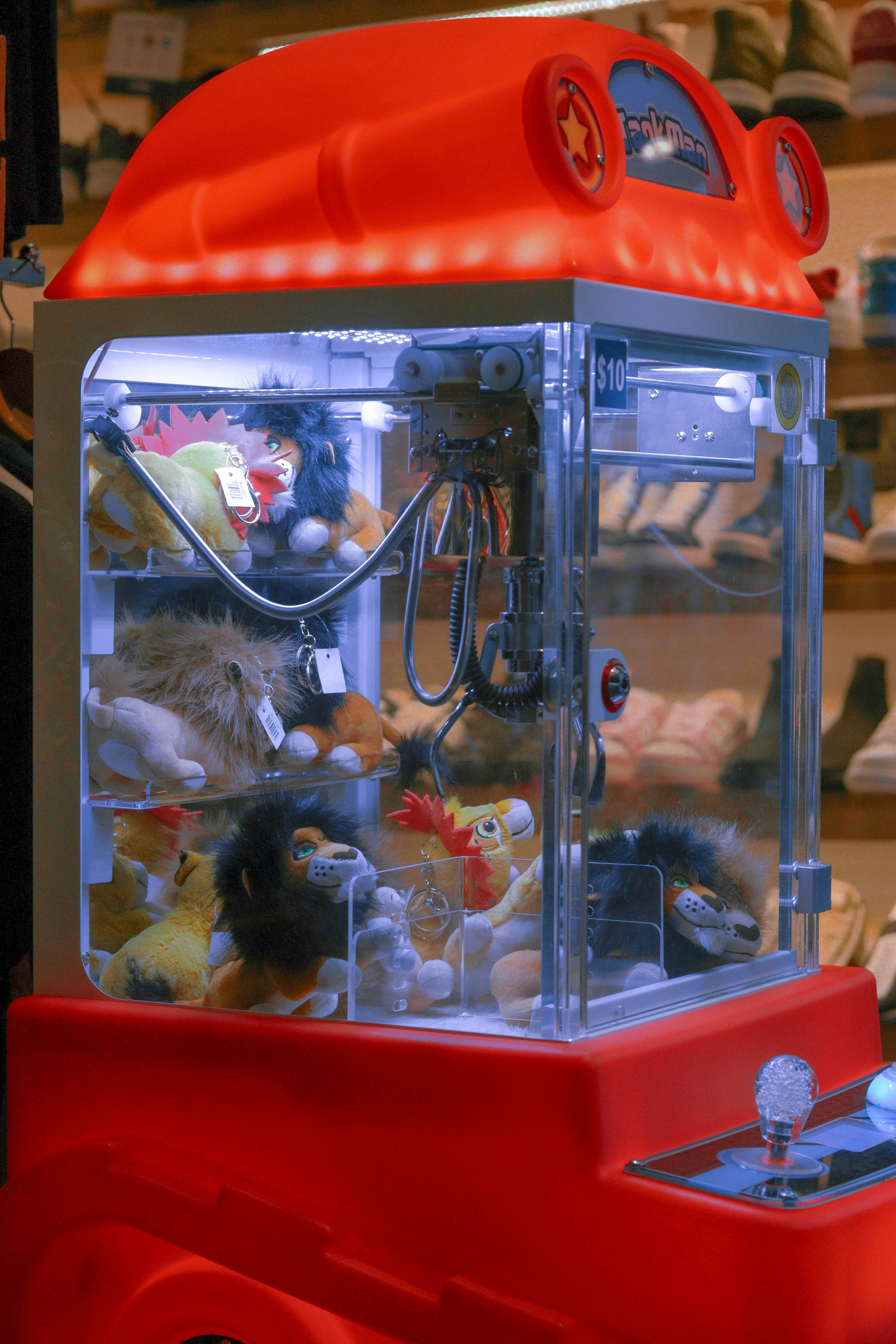 Crimson Capsule of Plush: Neon Claw Machine Guarding a Toy Trove