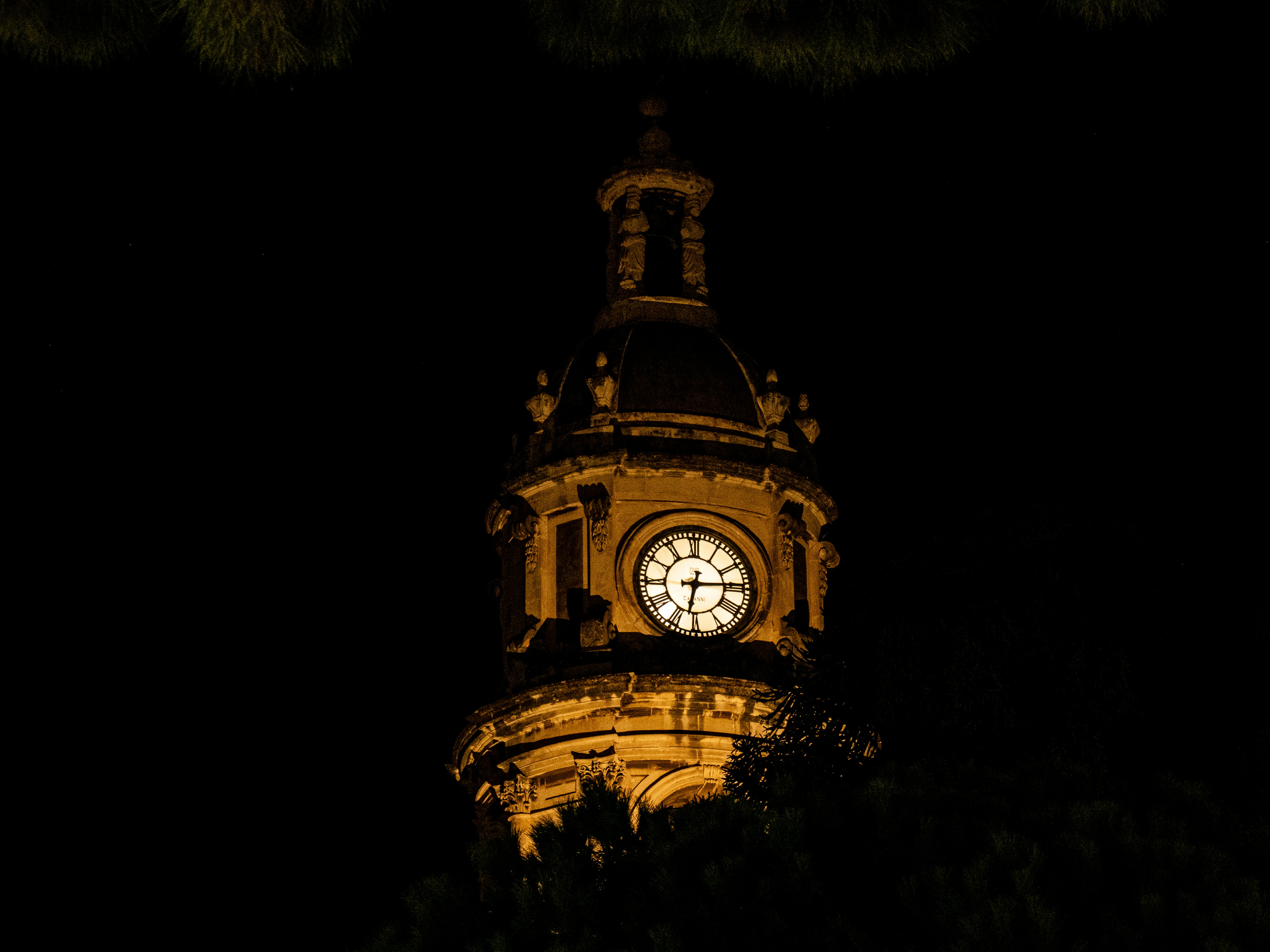 Illuminated clock tower against a dark night sky.