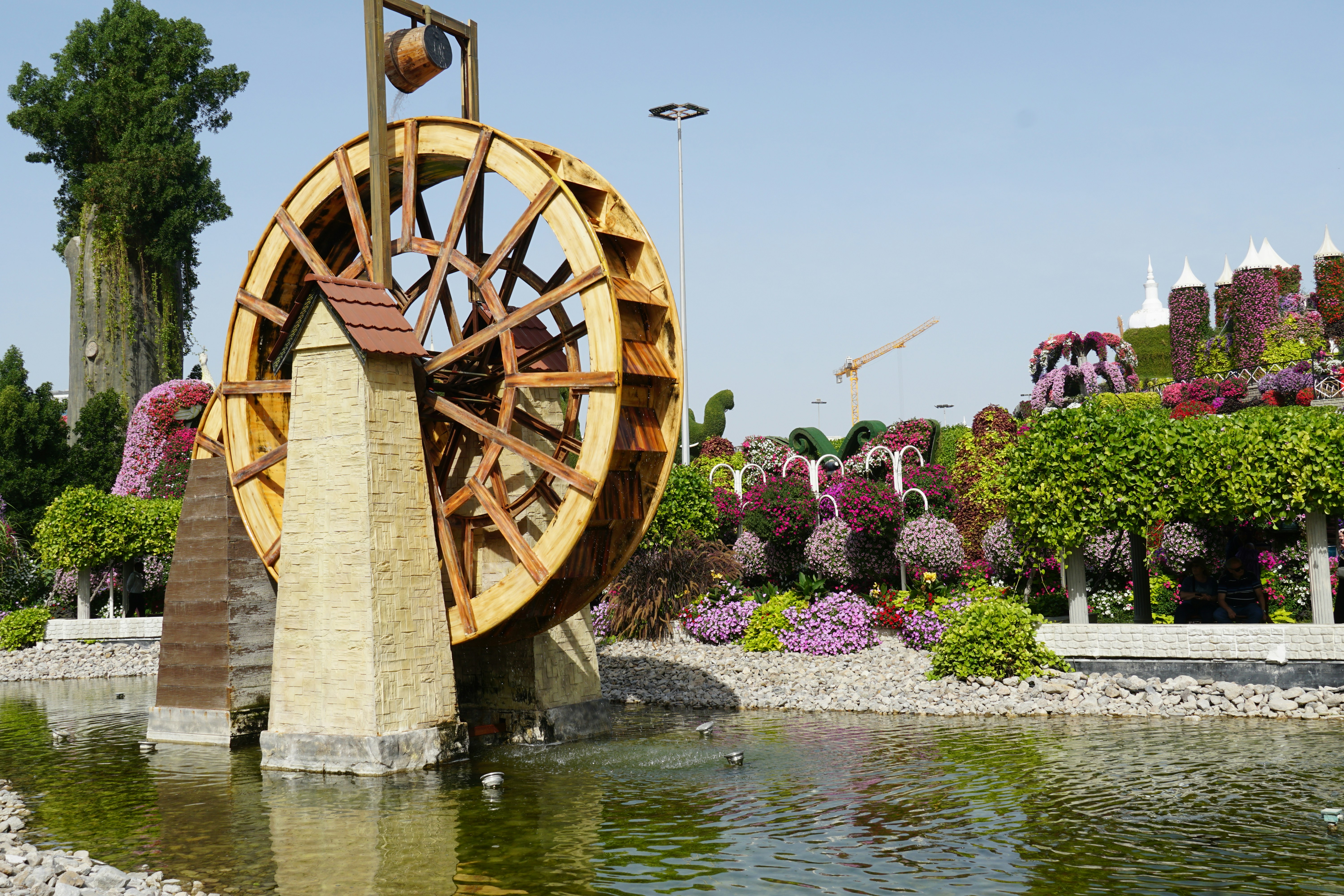 A large water wheel sitting in the middle of a park photo – Free ...