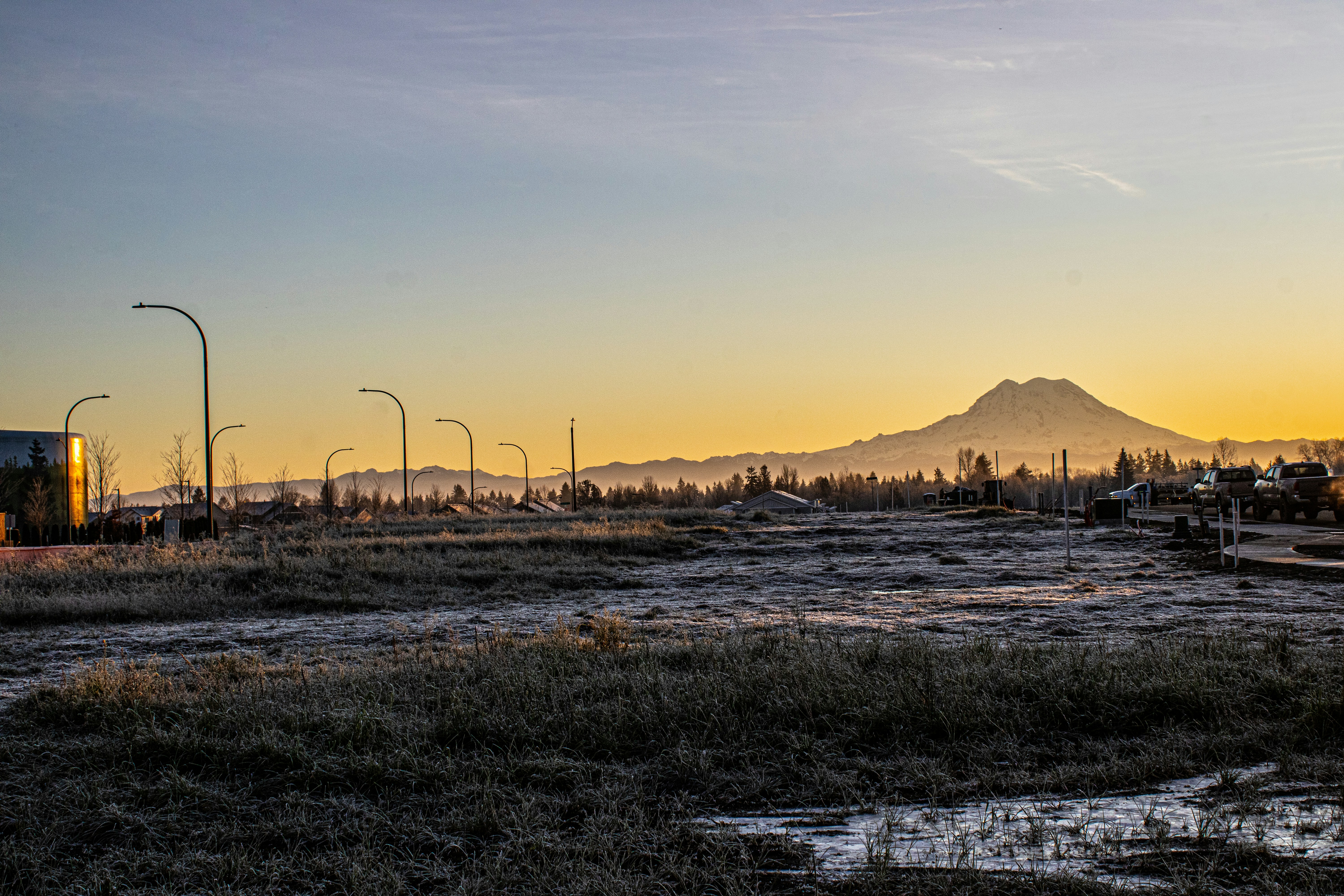 Frost-covered field with distant mountain under a vibrant sunrise.