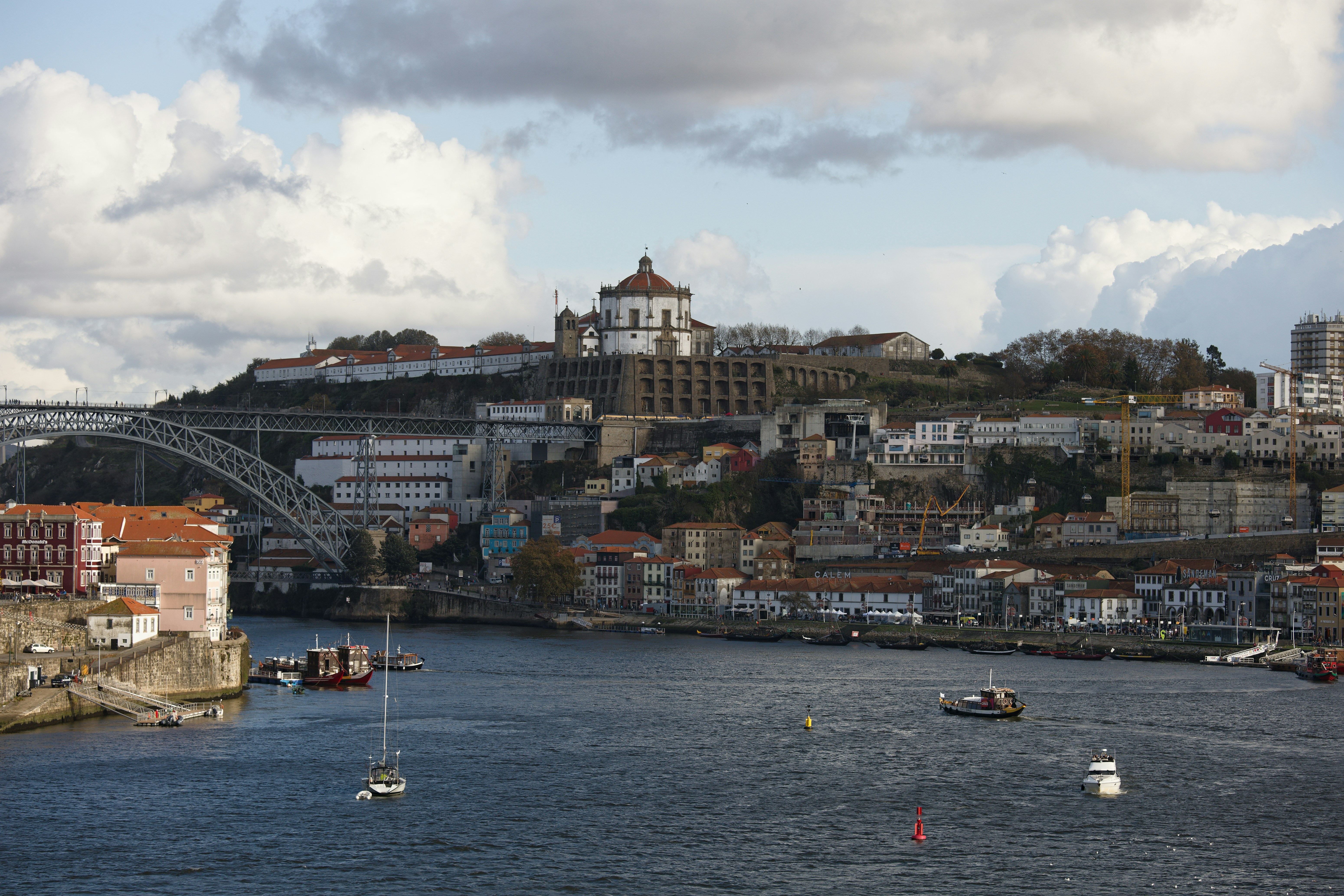 Scenic river view with small boats and historic architecture under a cloudy sky.