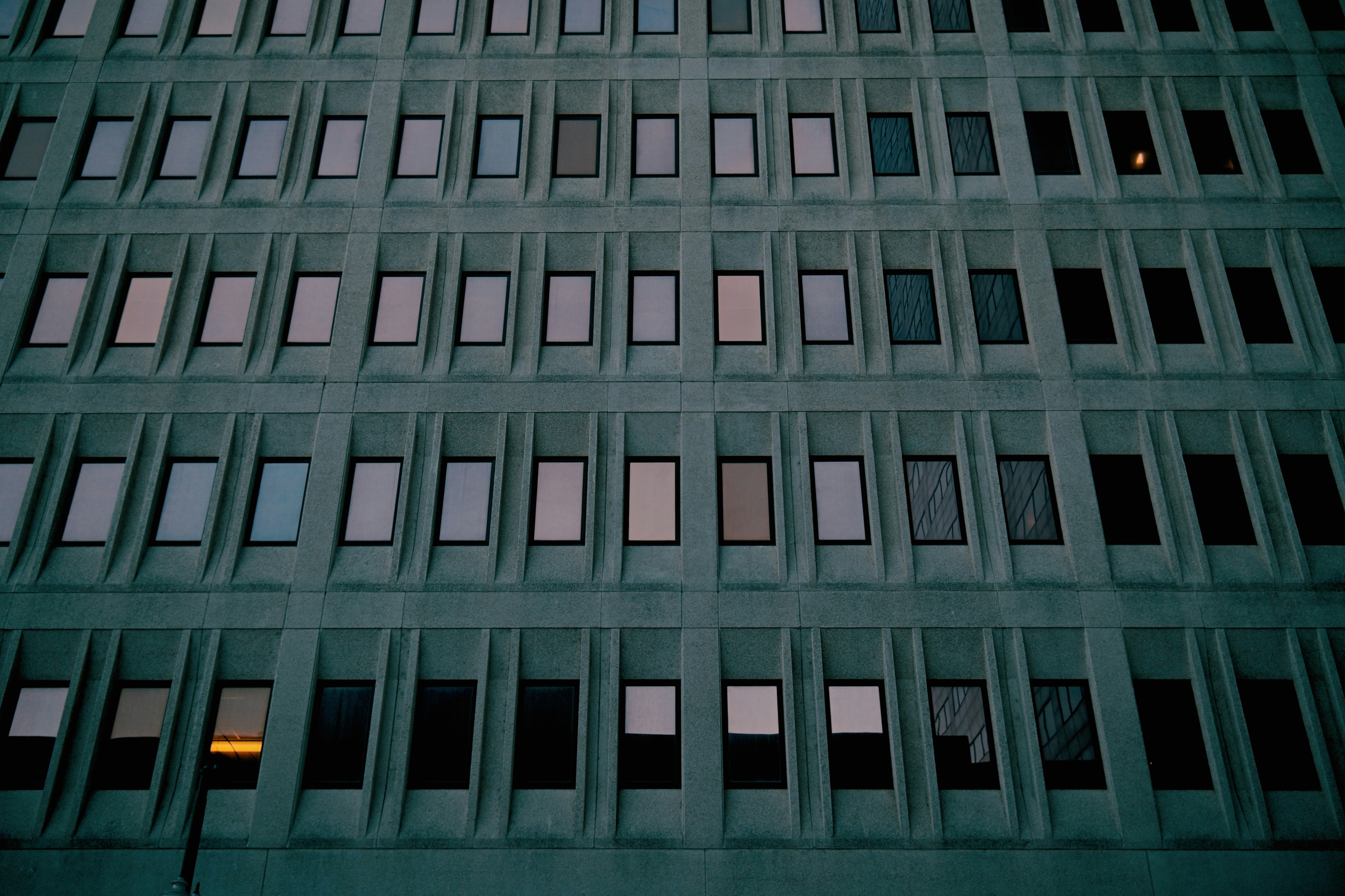 Facade of an office building with rows of windows reflecting various colors as evening sets in.