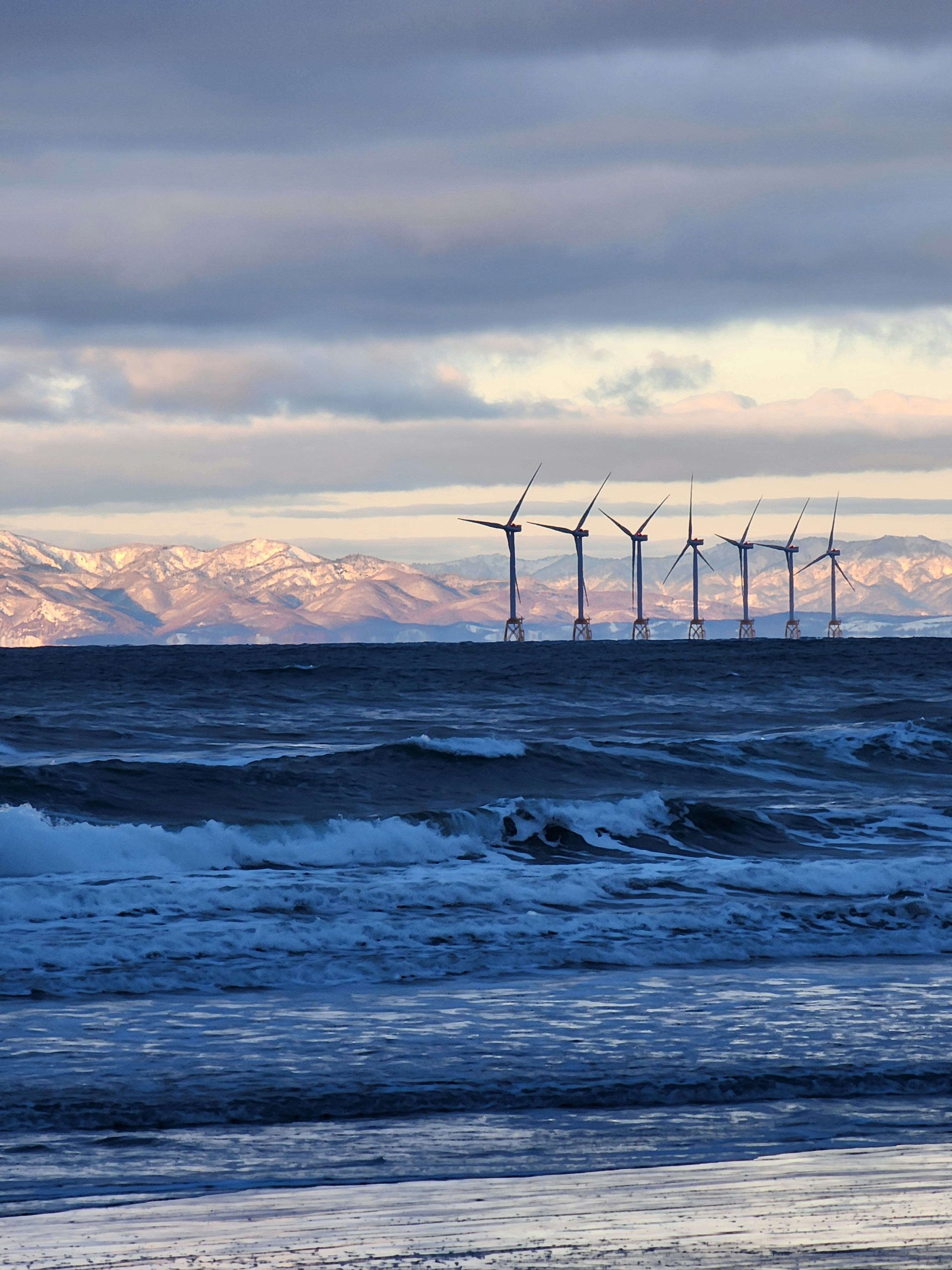 A wind farm in the distance with mountains in the background photo ...