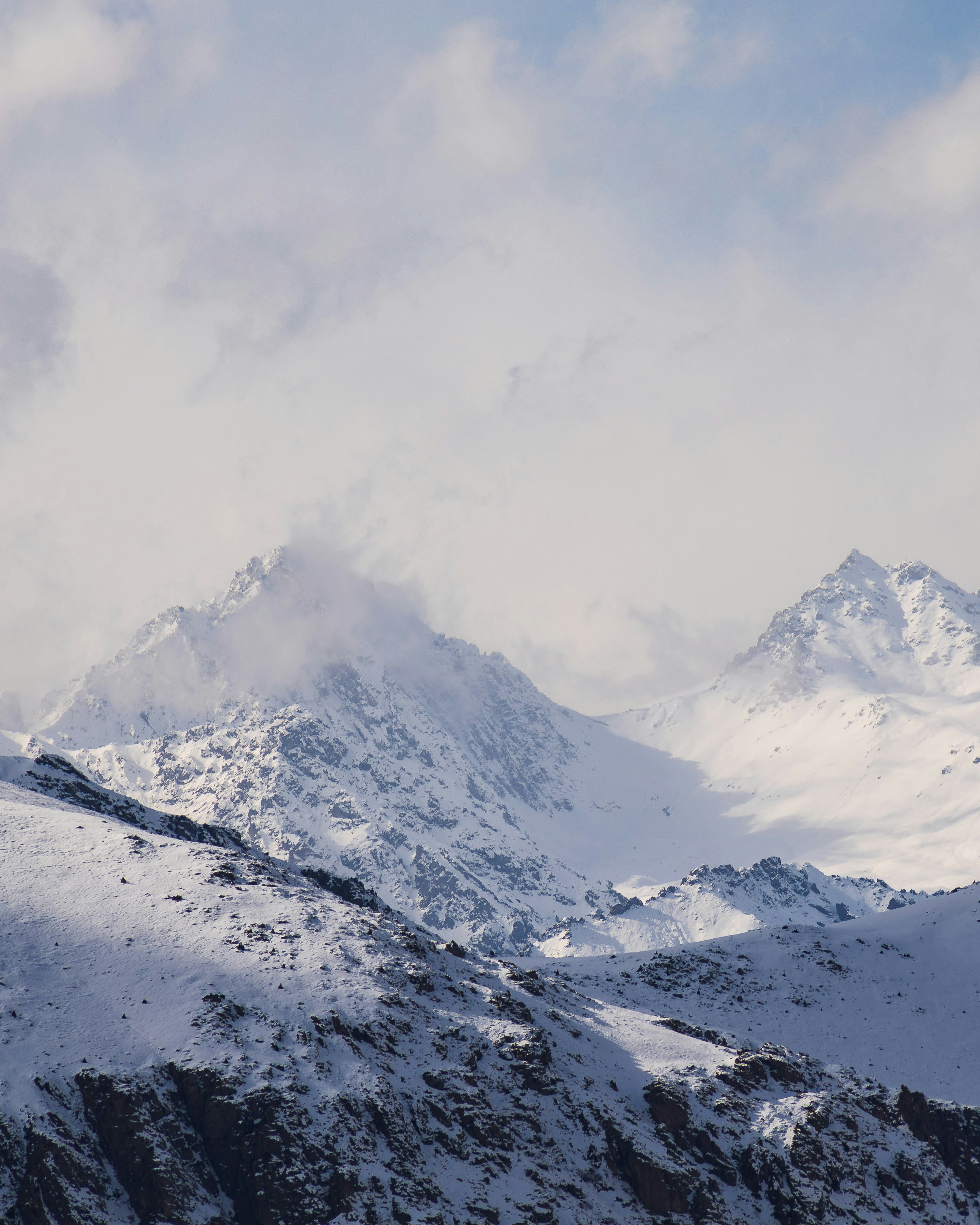 A snow covered mountain range under a cloudy sky photo – Free Mountains ...