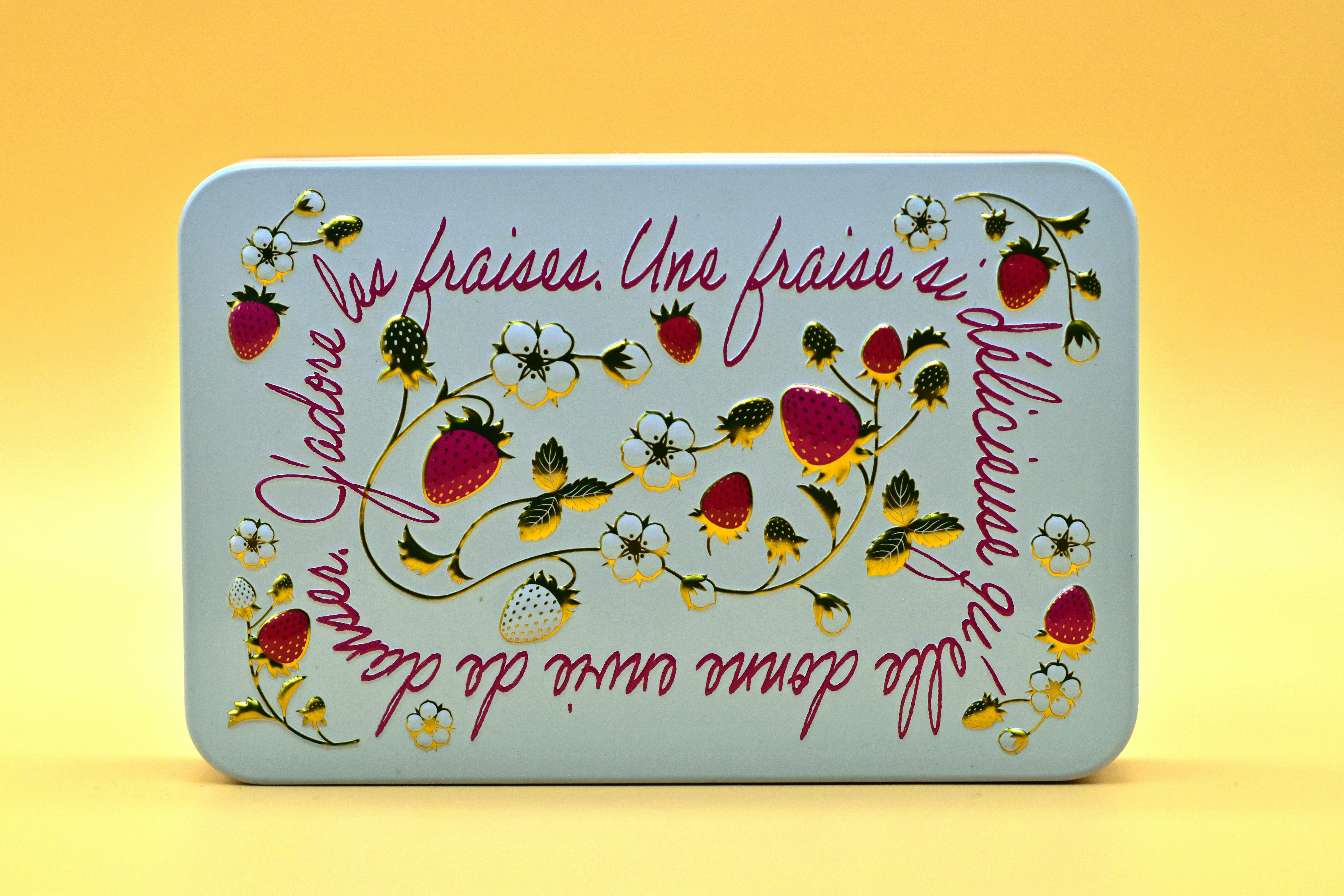 A small tin box with a picture of a strawberry on it