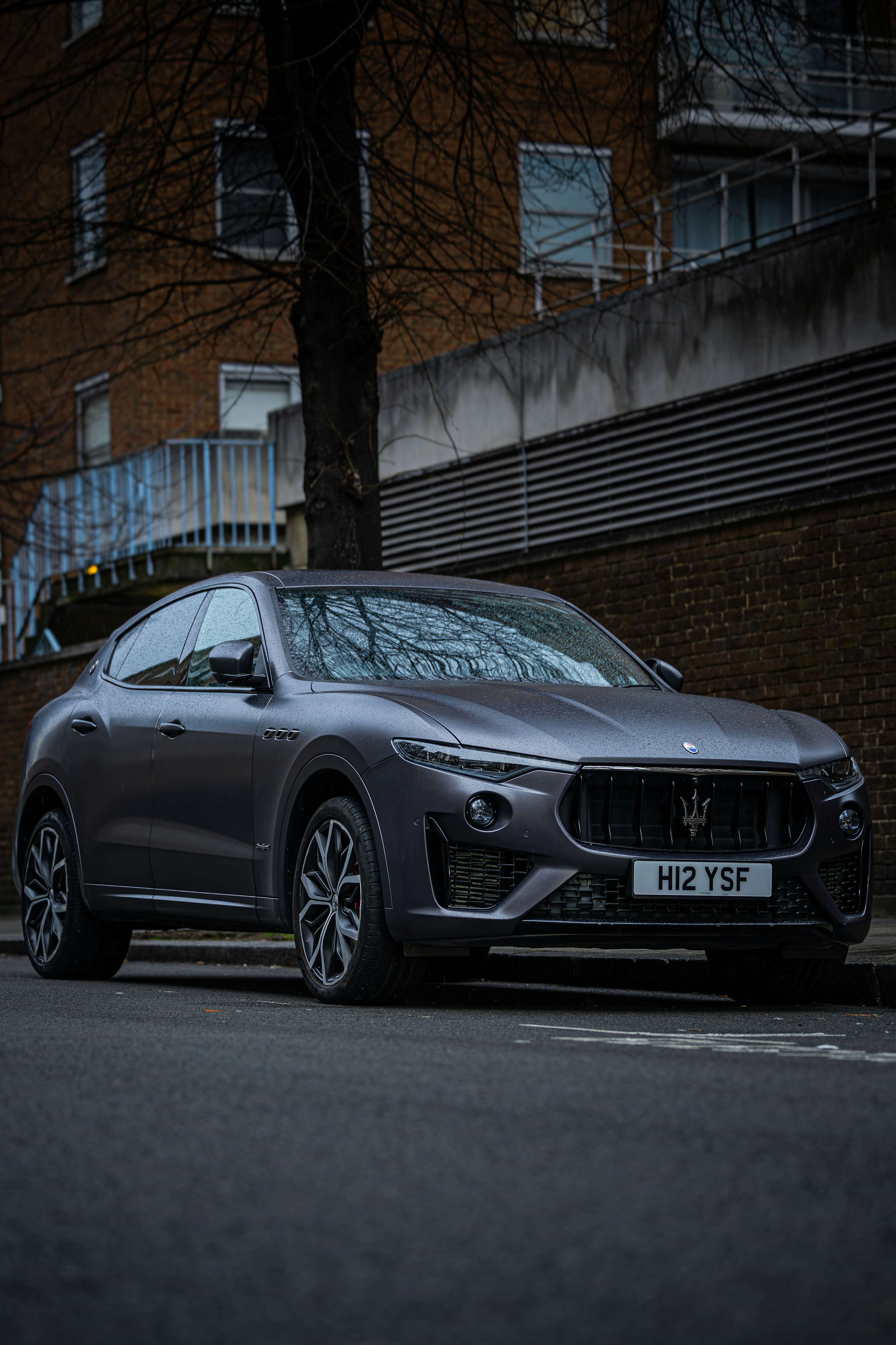 Maserati on the Street: Steel‑Grey Stance by the Brick Wall