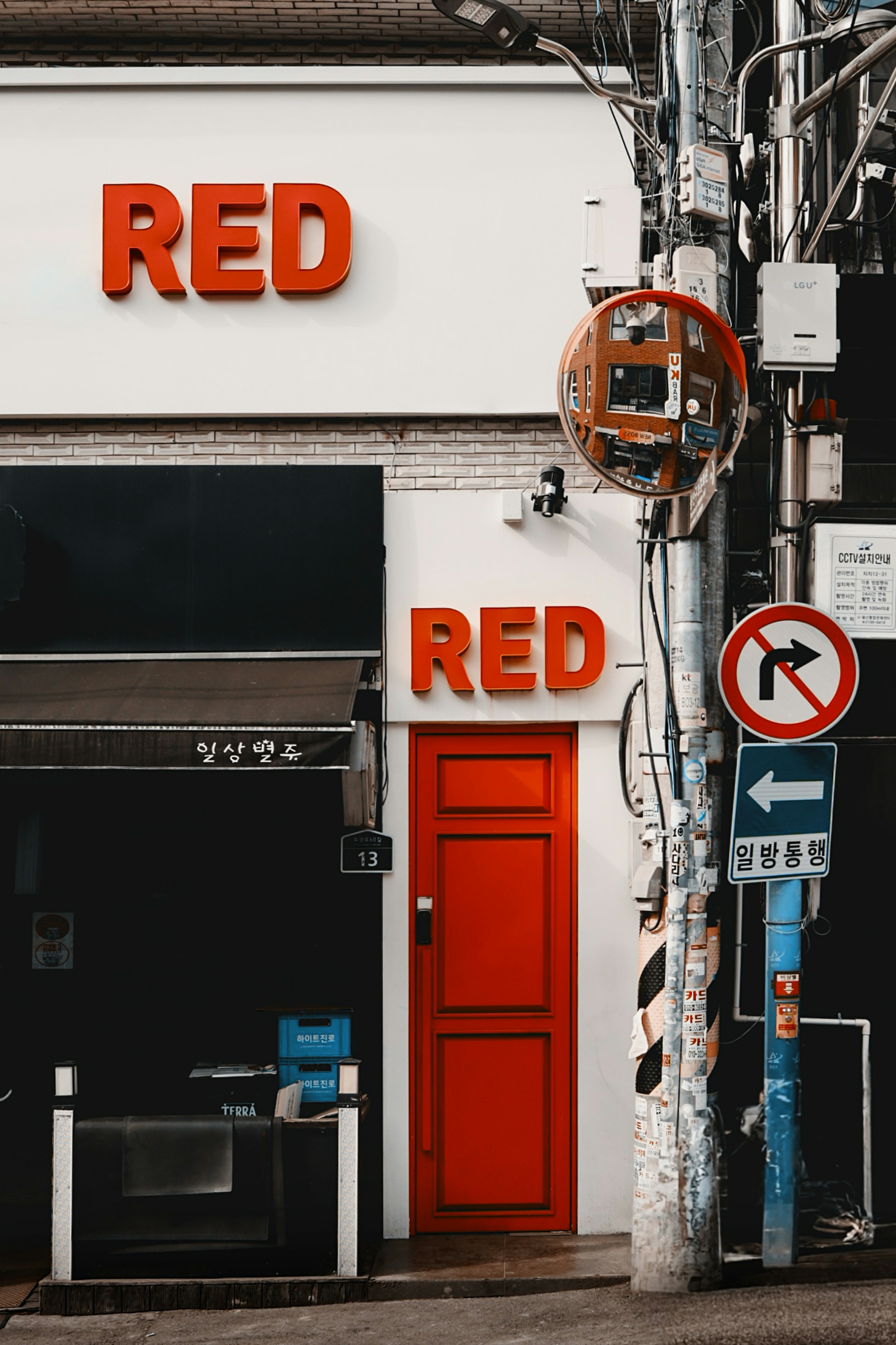 Crimson Threshold: Red Door Framed by White Facade and Urban Reflections