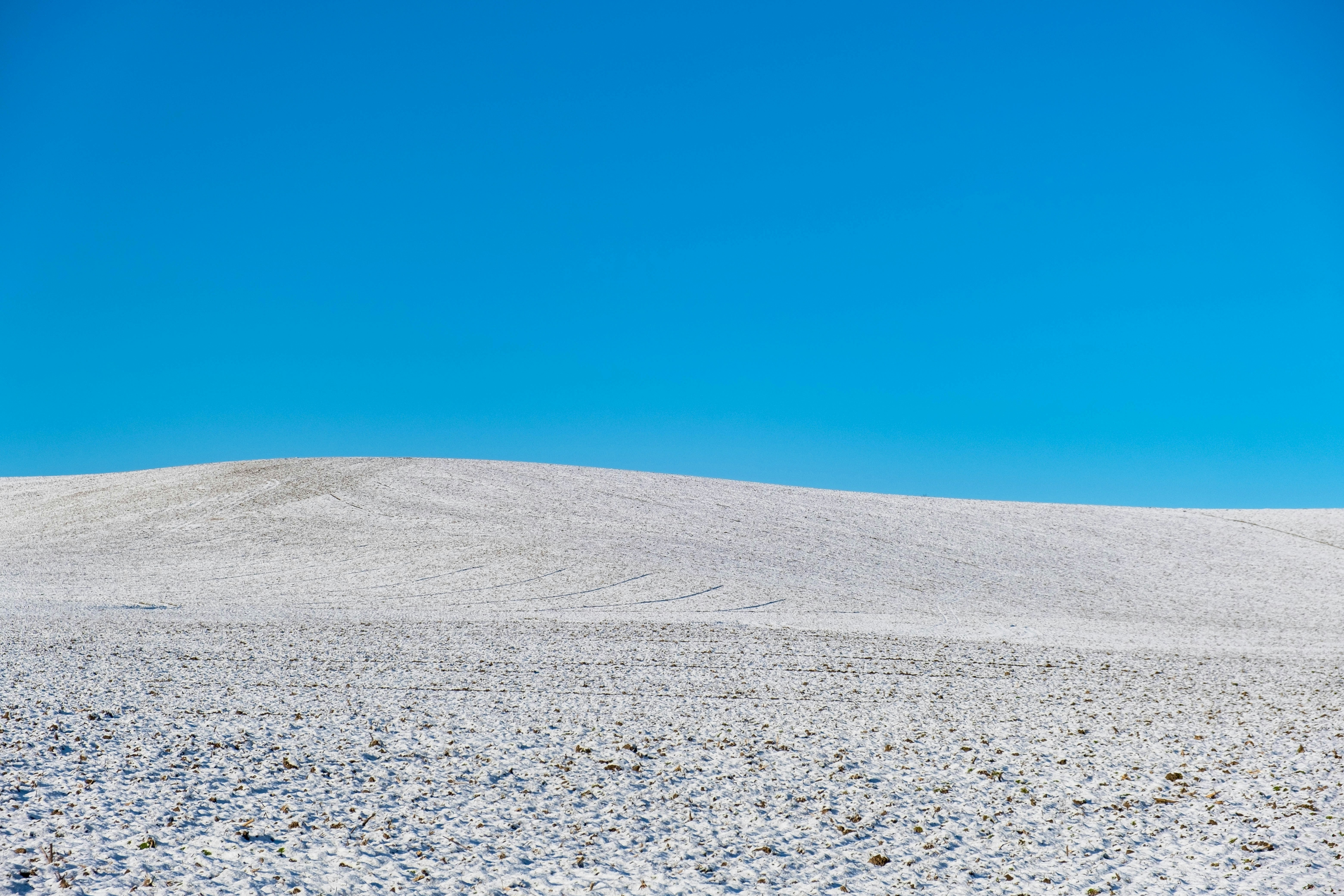 A snow covered field with a blue sky in the background photo – Free ...