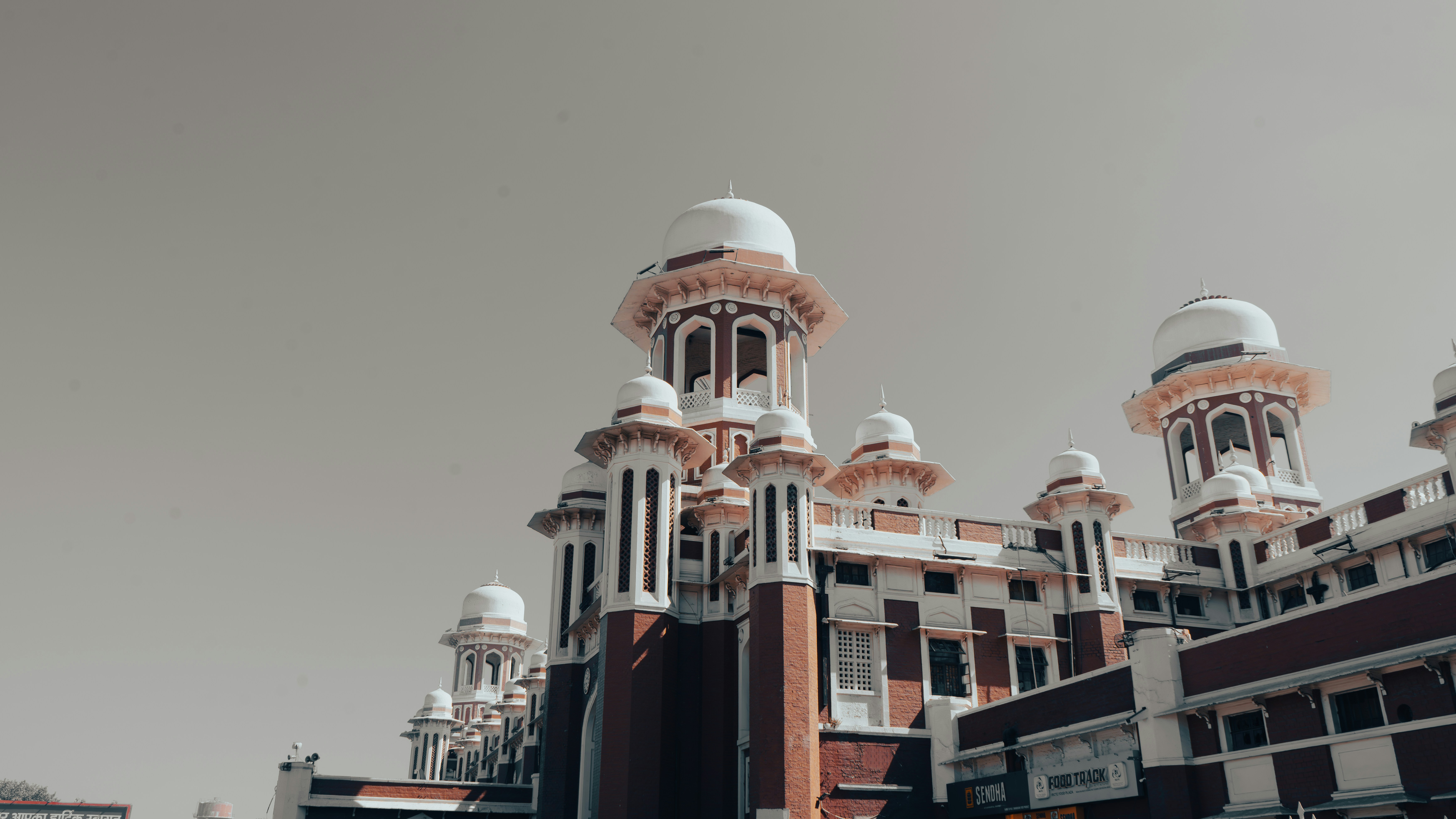 Ornate building with white domes and red brick accents under a clear sky.